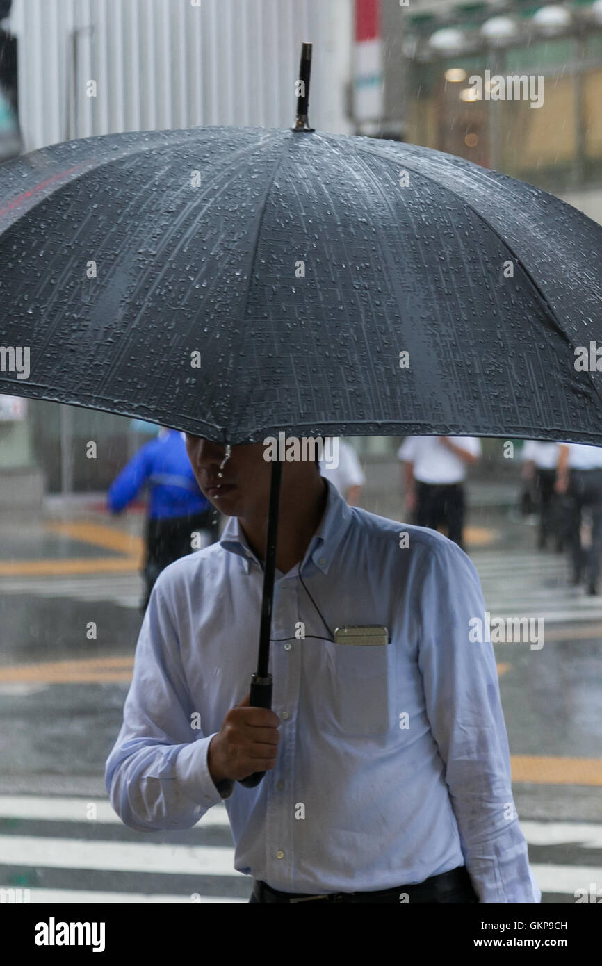 Tokyo, Japan. 22nd Aug, 2016. A man holds an umbrella under the rain in ...