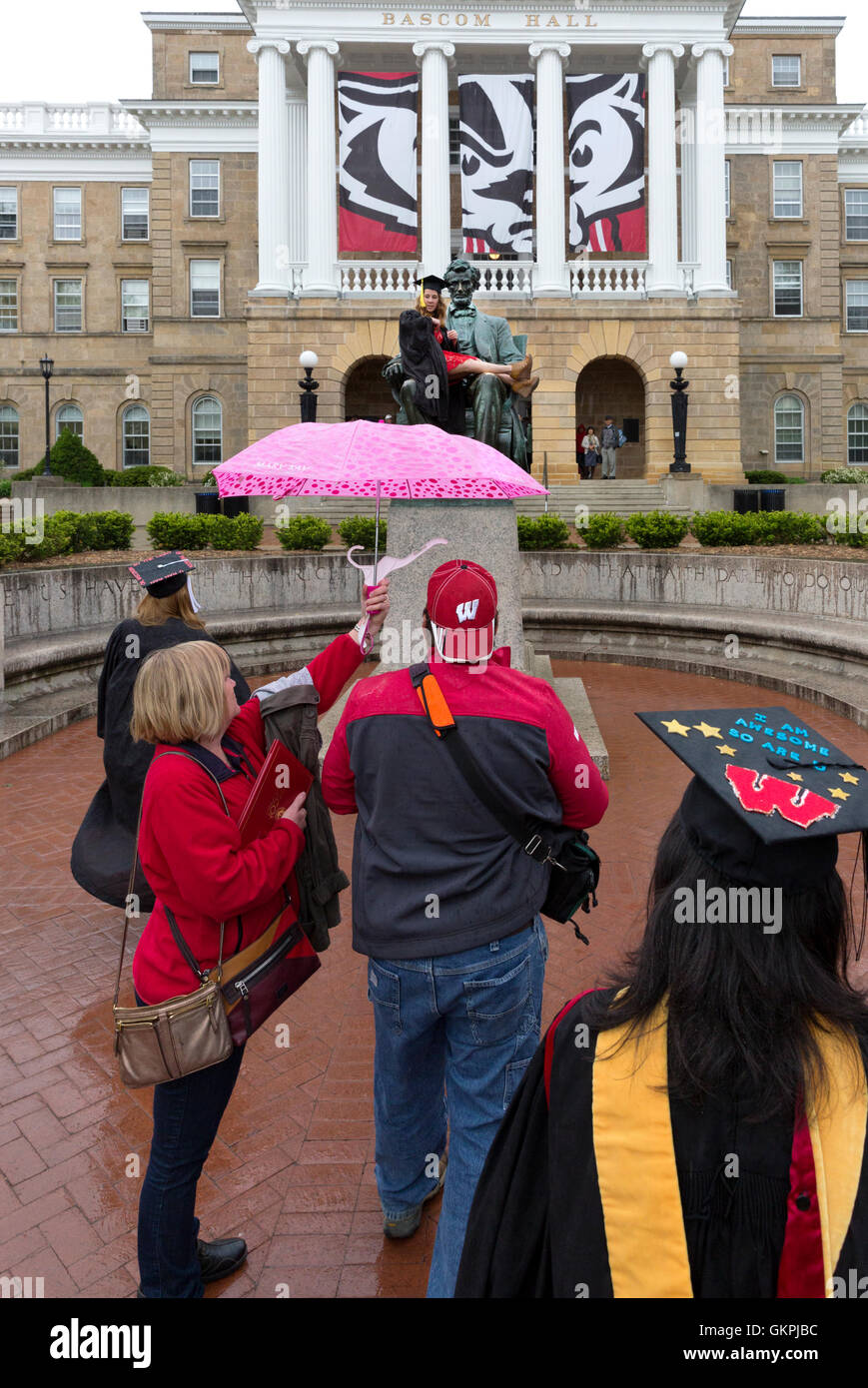 A graduate in the rain having her photo taken on the campus of the ...