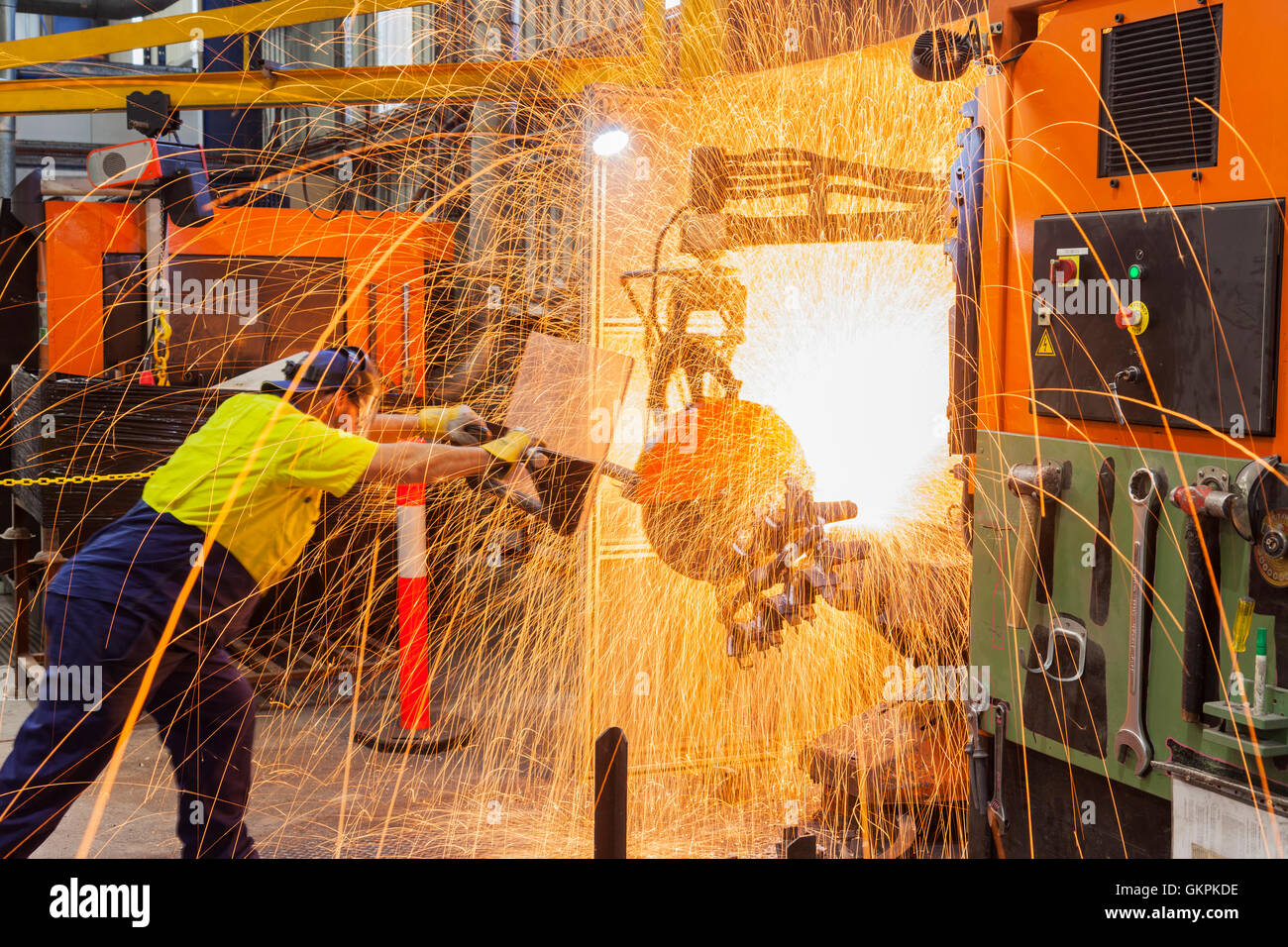 workman grinding and cutting away cast metal components from its ...