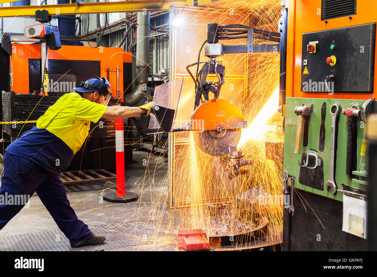 workman grinding and cutting away cast metal components from its ...