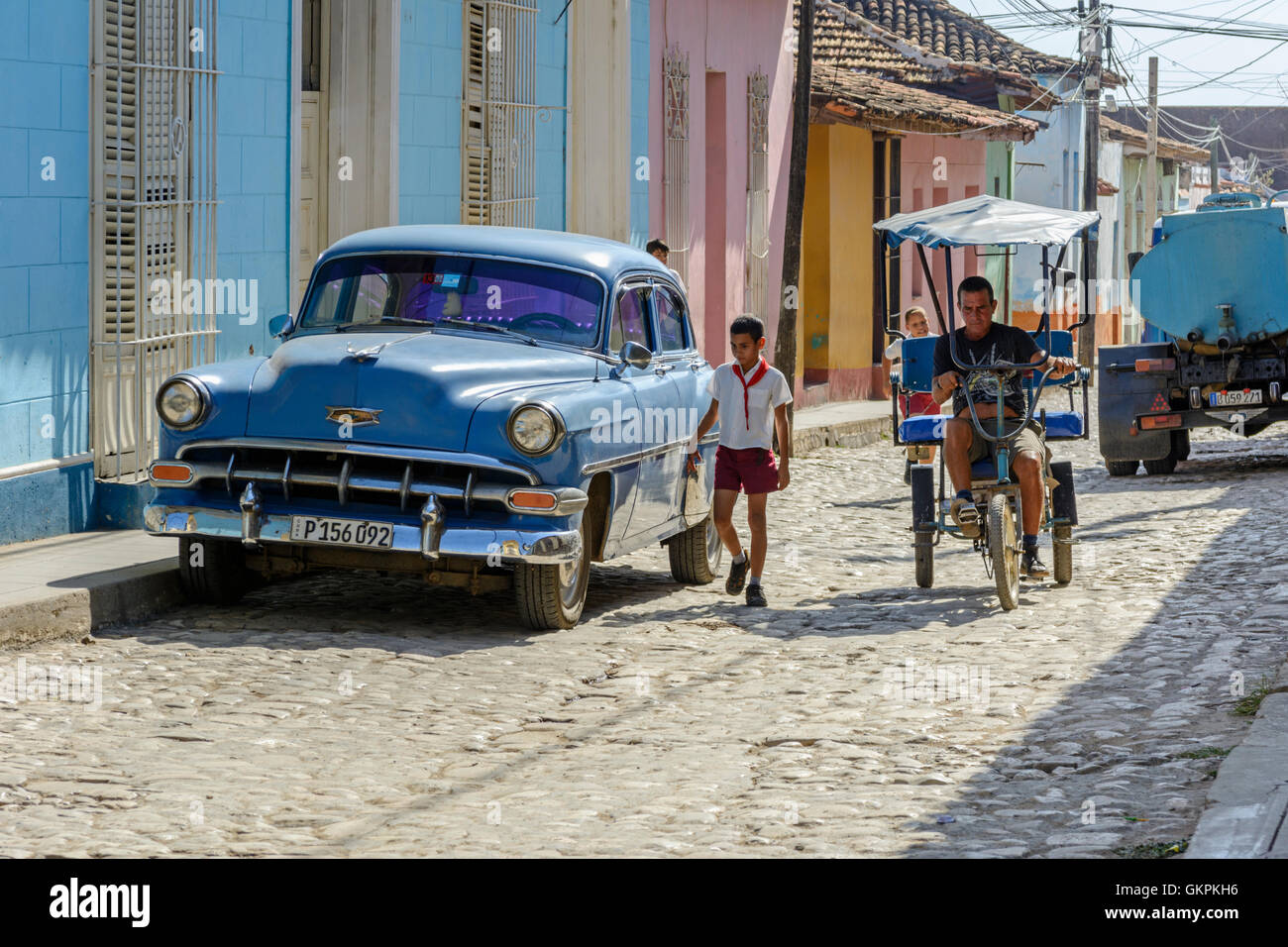 Street scene with a classic American car, a bicycle taxi and a young ...