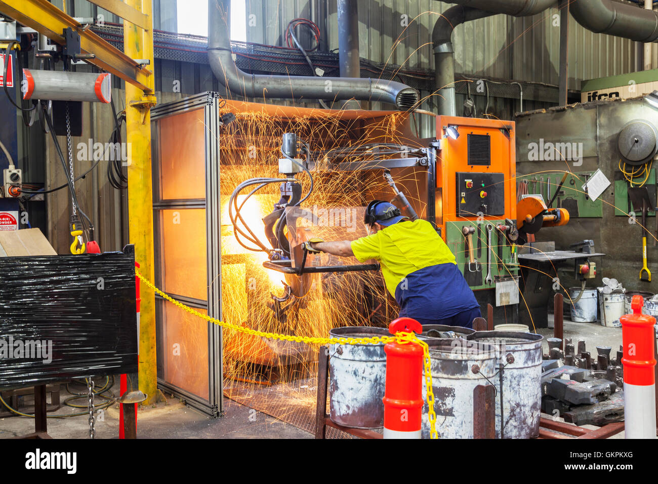 workman grinding and cutting away cast metal components from its ...
