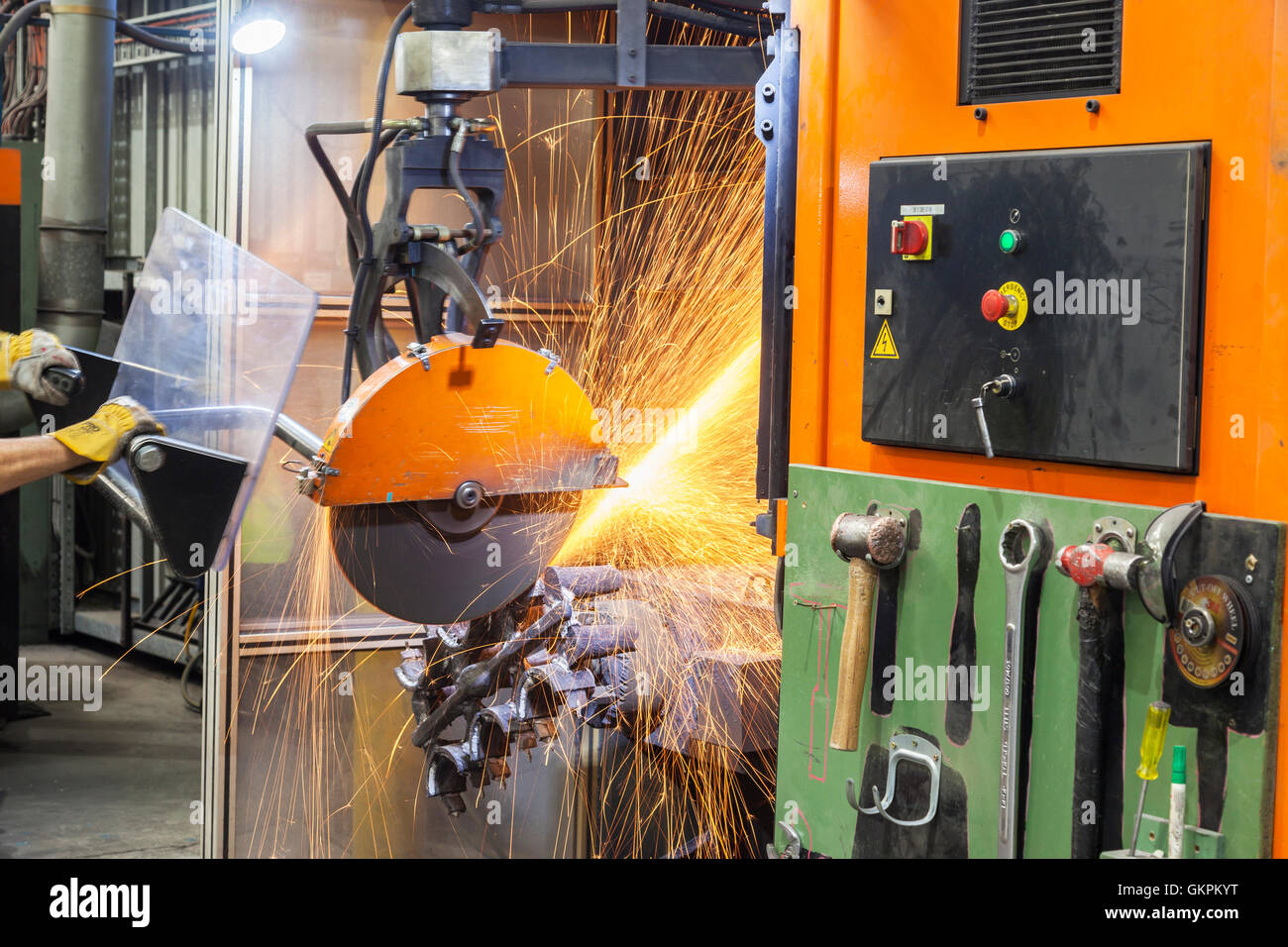 workman grinding and cutting away cast metal components from its ...