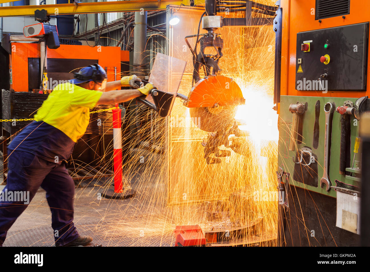 workman grinding and cutting away cast metal components from its ...