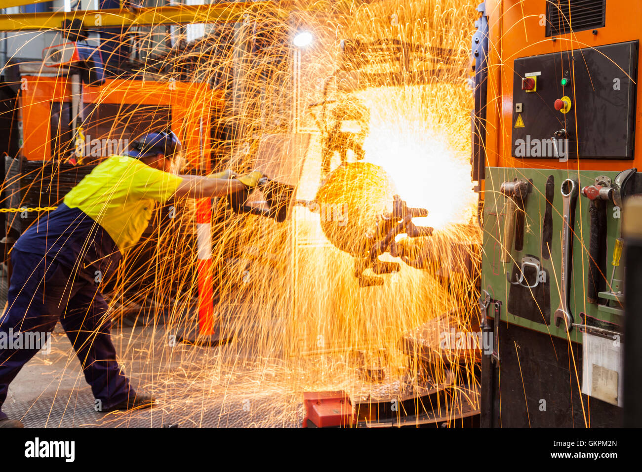 workman grinding and cutting away cast metal components from its ...