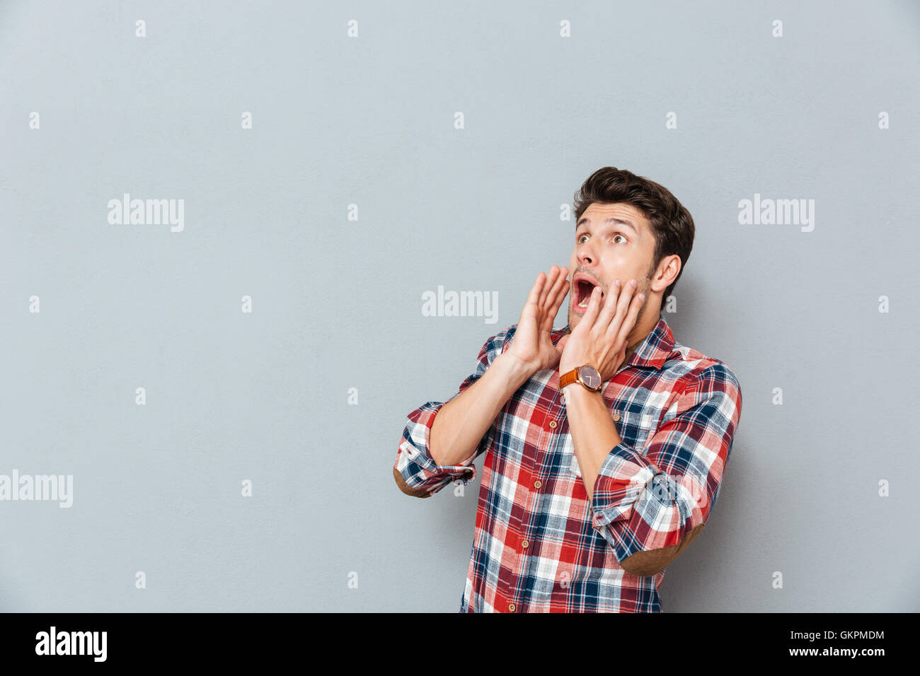Scared shocked young man in plaid shirt looking away and shouting over ...