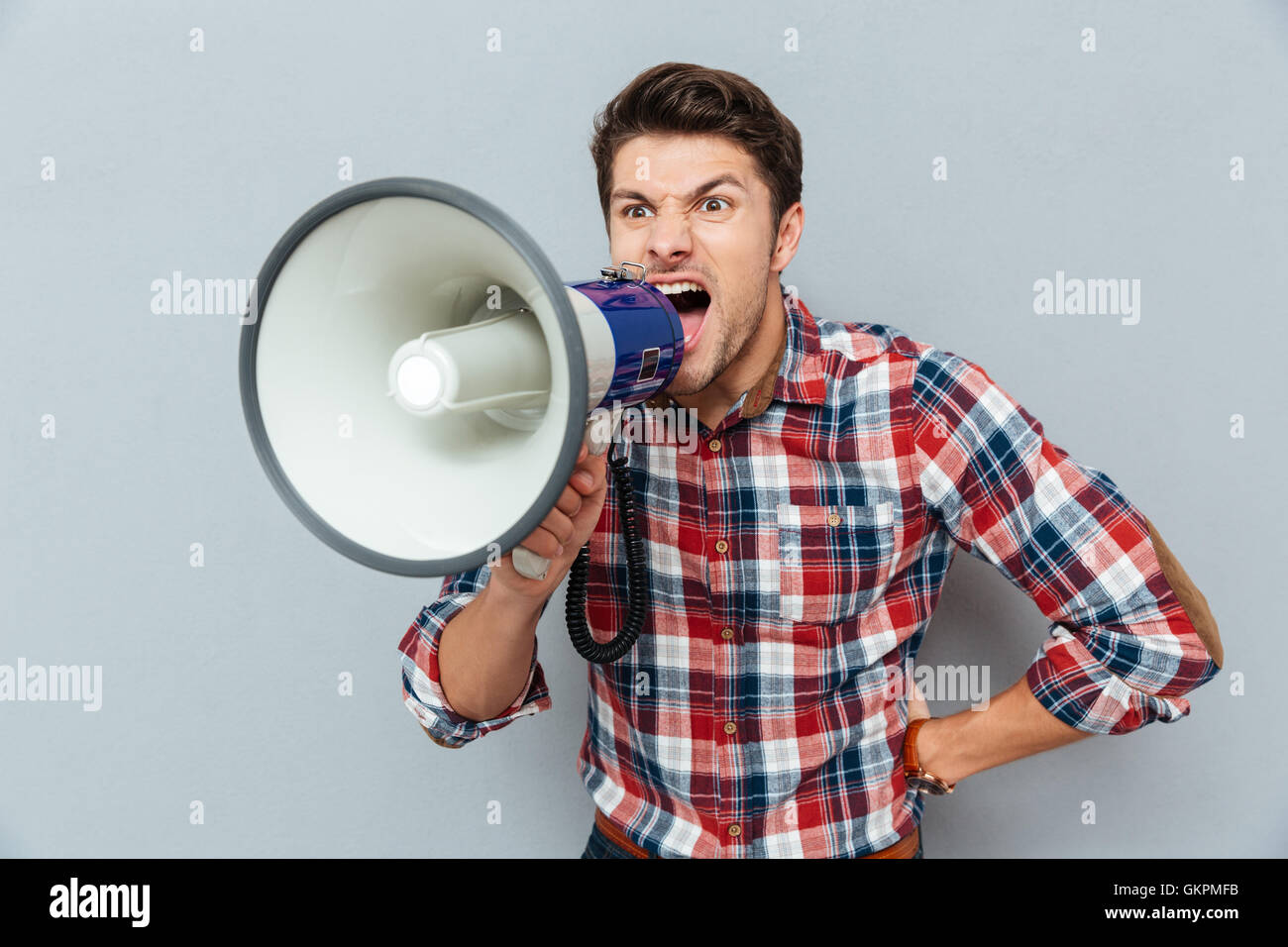 Furious aggressive young man in checkered shirt standing and shouting ...