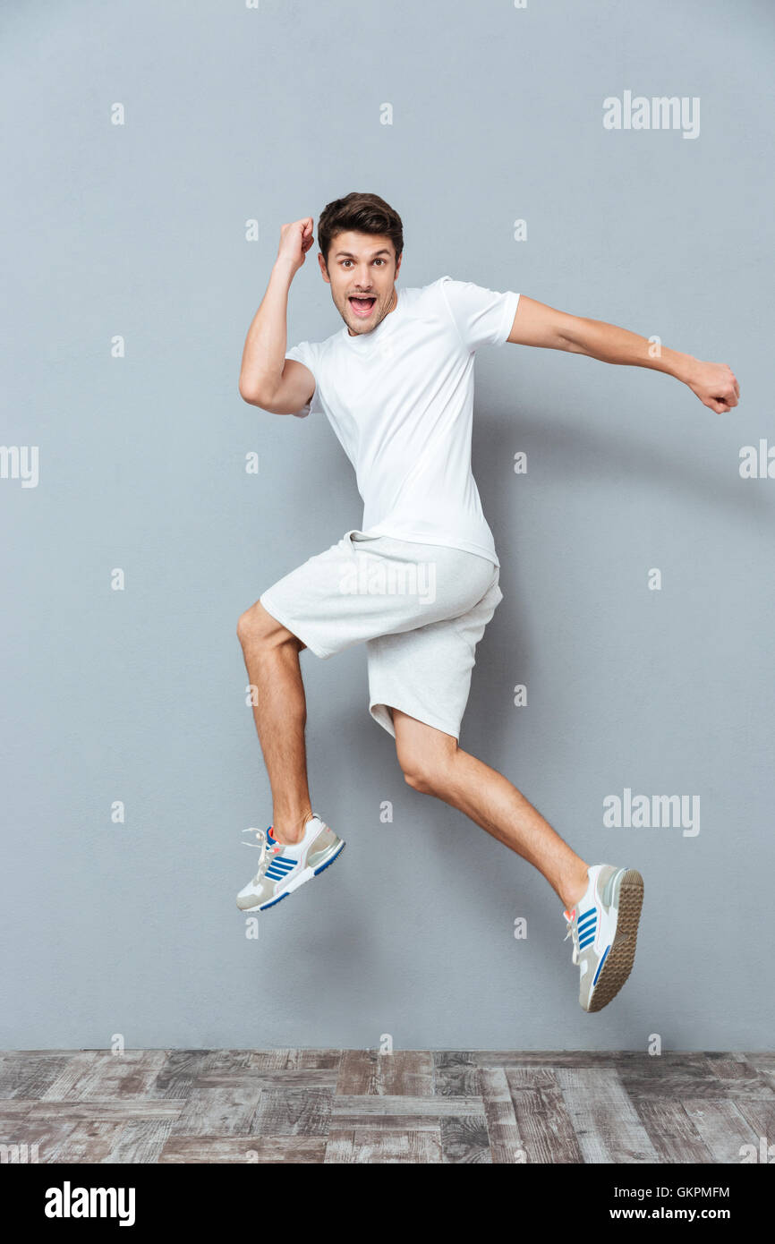 Funny crazy man jumping over gray background Stock Photo - Alamy