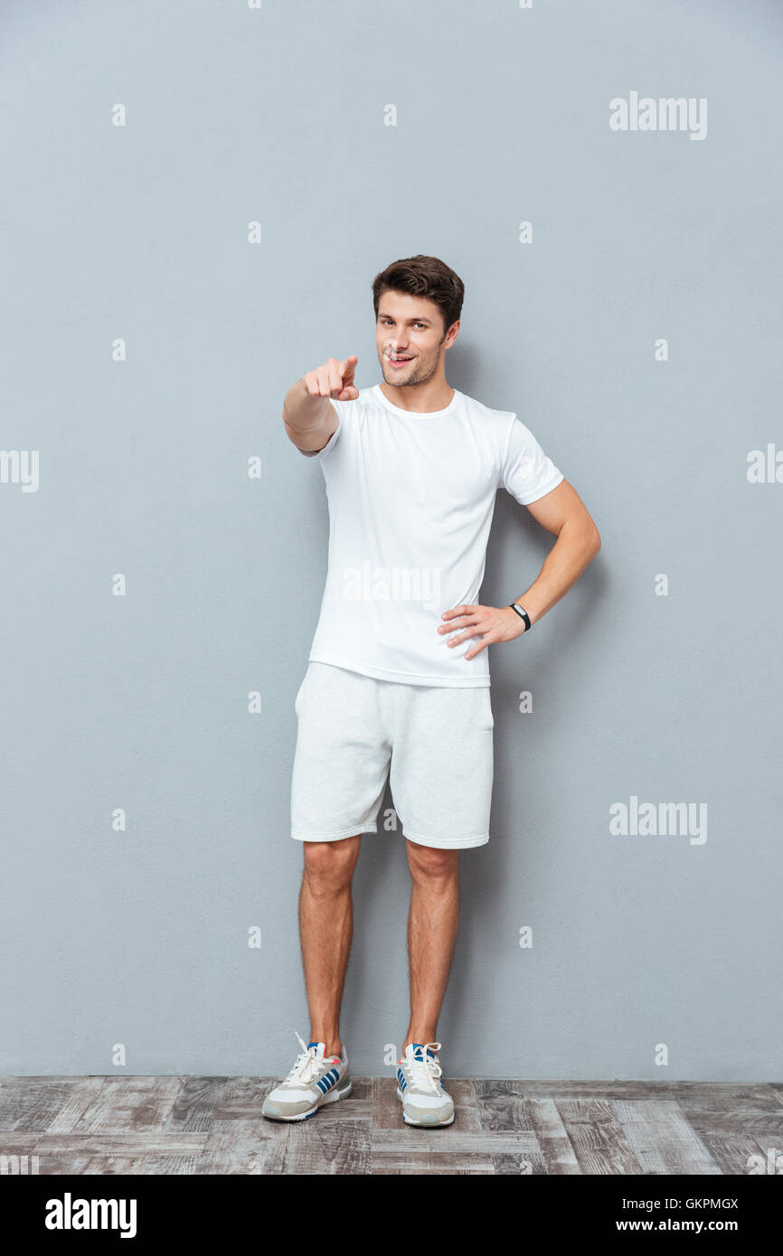 Full length of handsome smiling young man standing and pointing on you ...