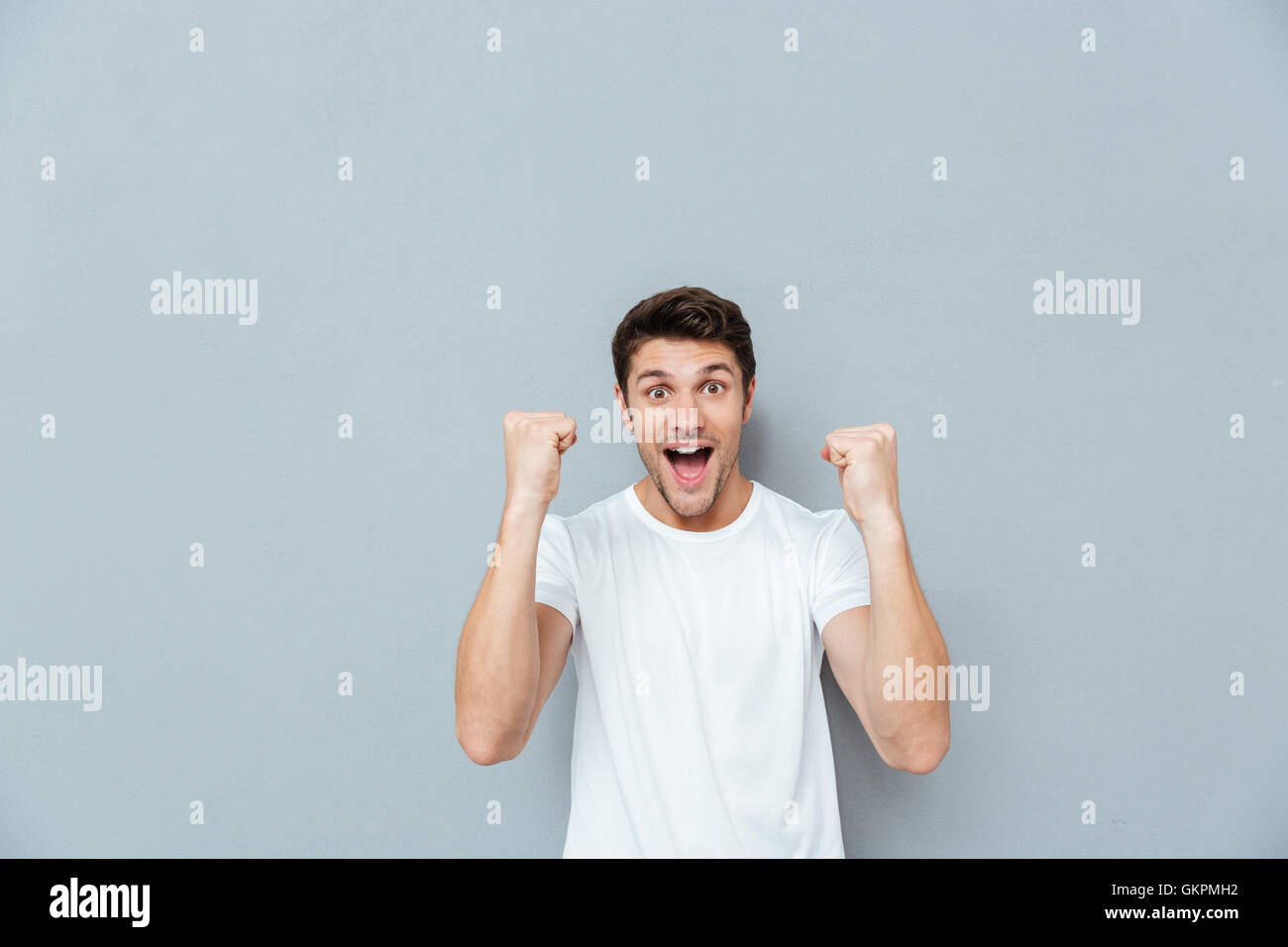 Happy excited young man shouting and celebrating success over grey ...