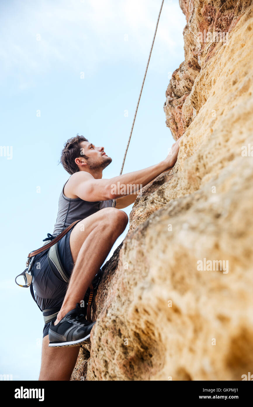 Young handsome sportsman climbing up a rock cliff Stock Photo - Alamy