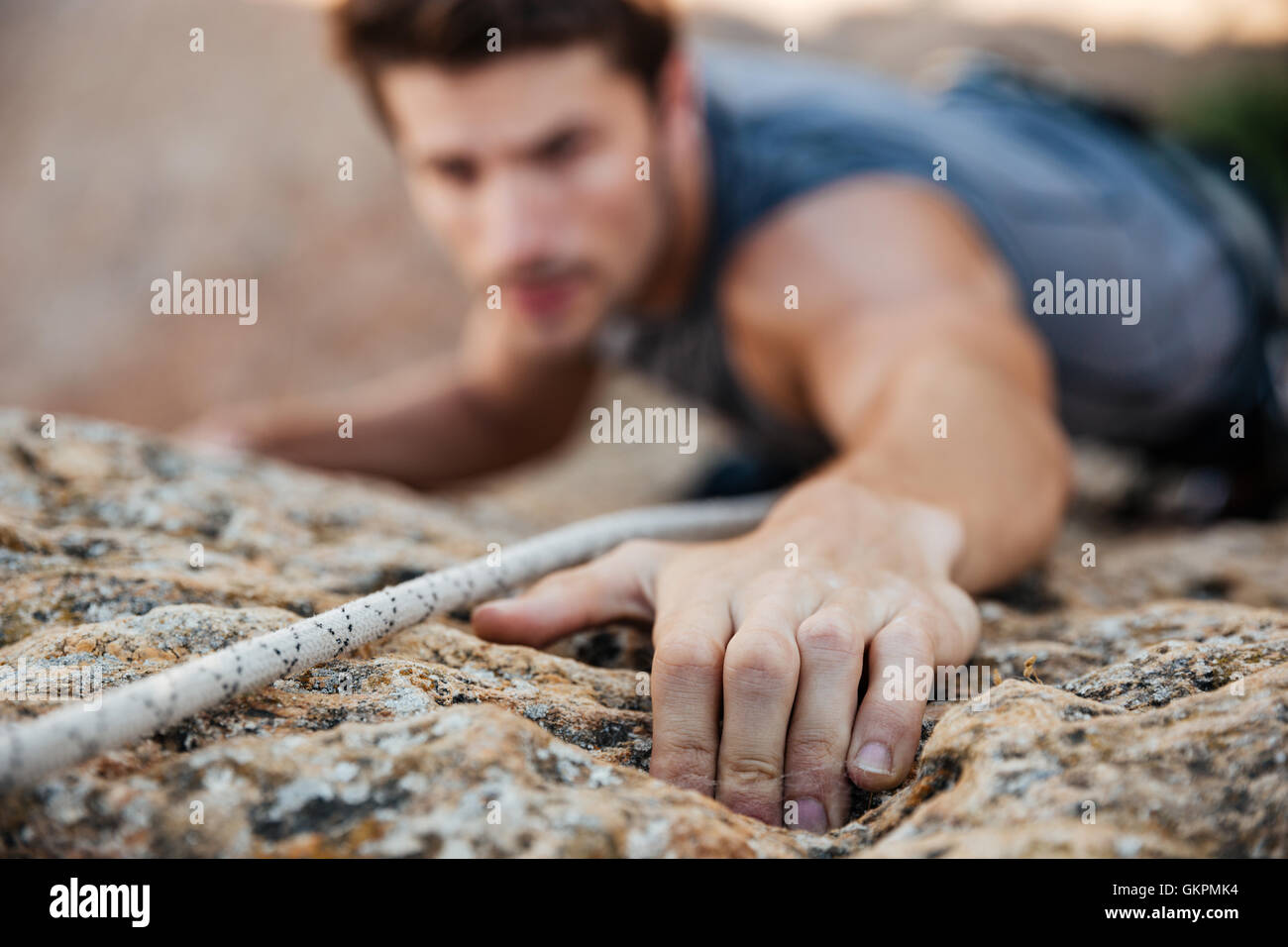Man reaching for a grip while he rock climbs on a steep cliff Stock ...