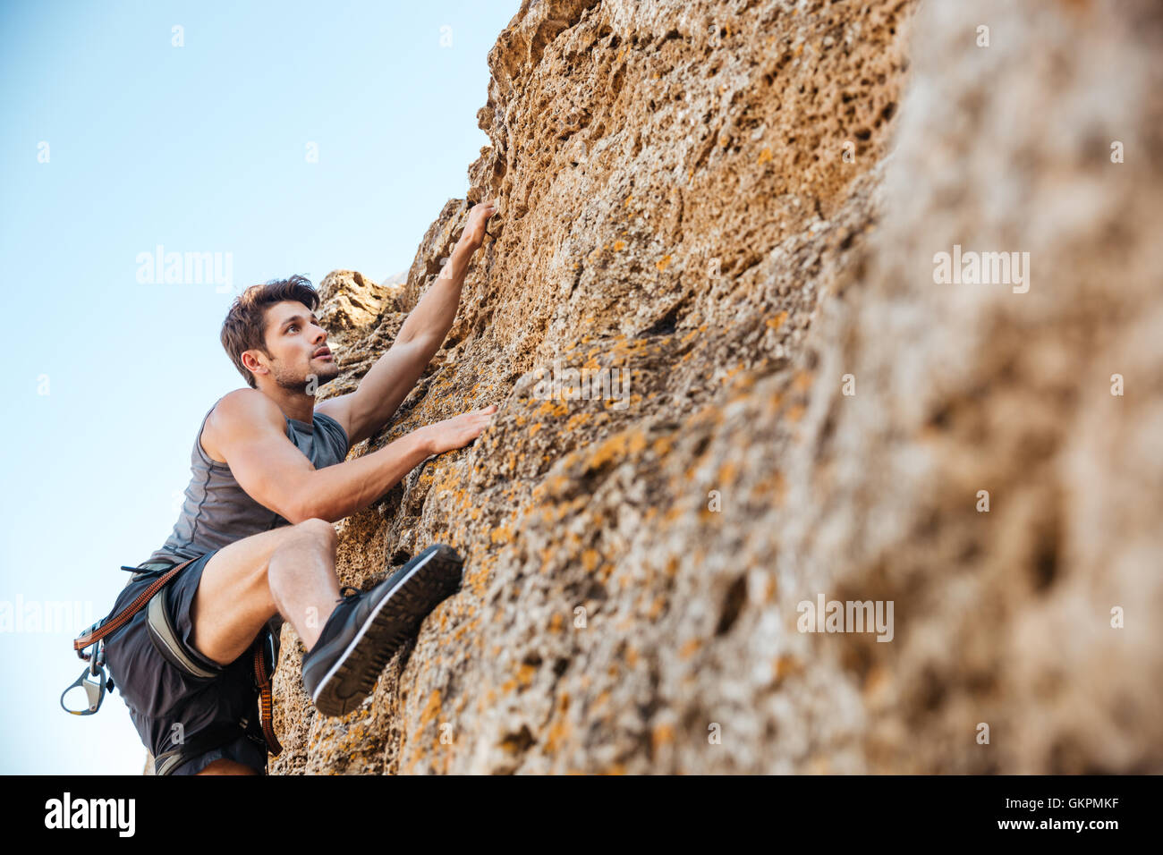 Young handsome sportsman climbing up a rock cliff Stock Photo - Alamy
