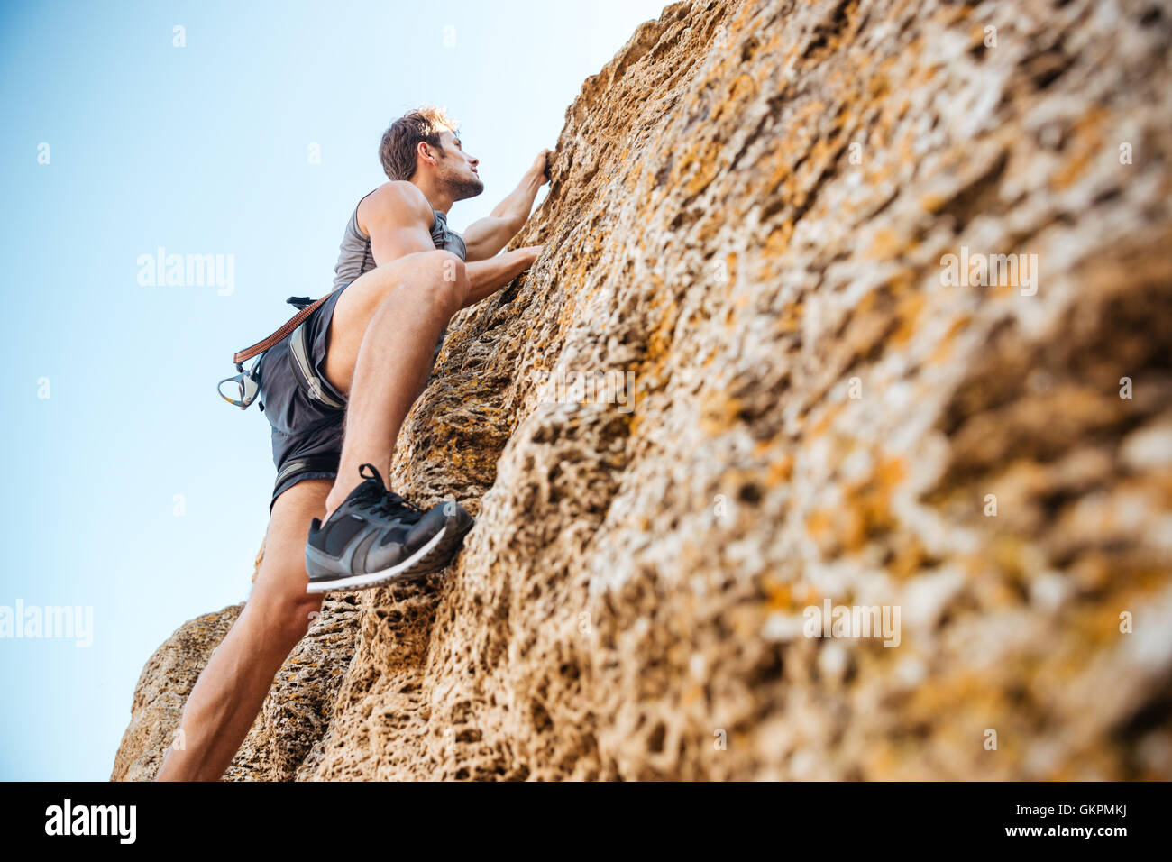 Young handsome sportsman climbing up a rock cliff Stock Photo - Alamy