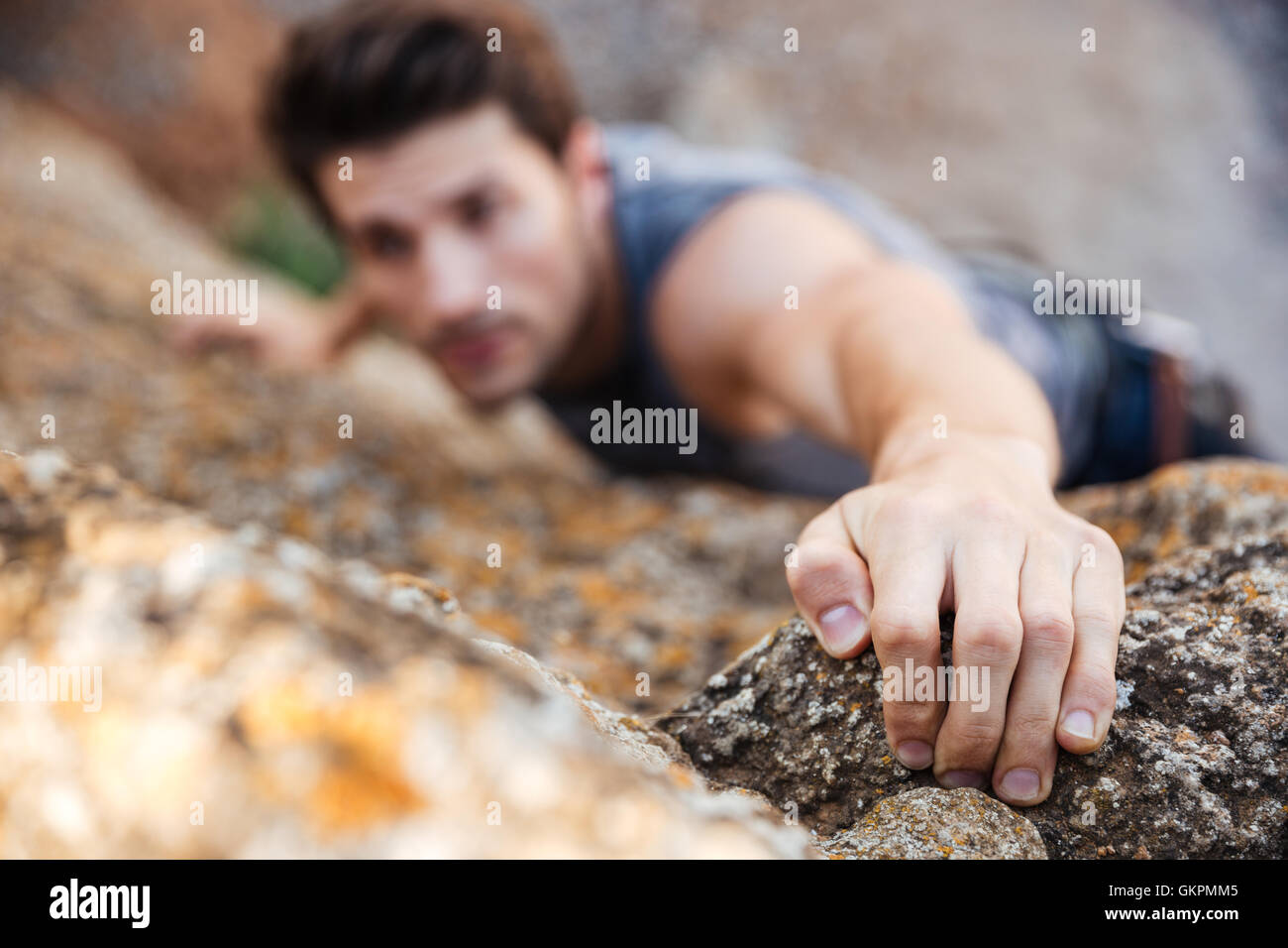 Man reaching for a grip while he rock climbs on a steep cliff Stock ...