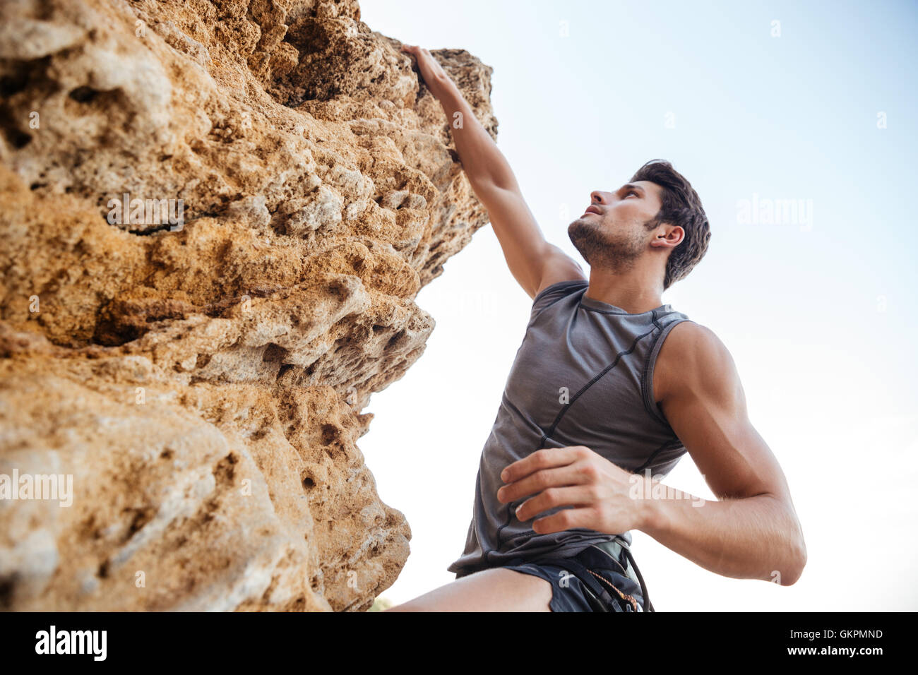 Man reaching for a grip while he rock climbs on a steep cliff Stock ...