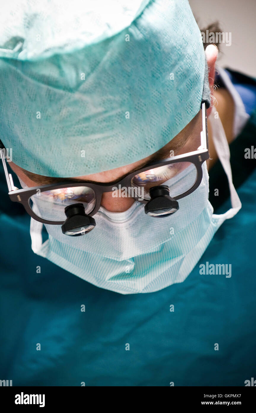 Close up of a surgeon working in a operating room wearing surgical ...