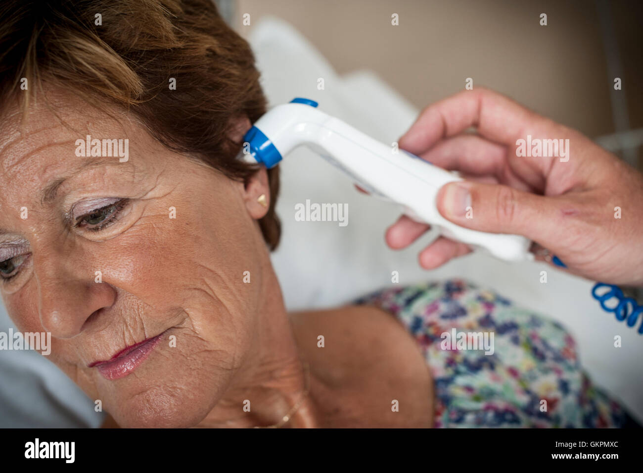Nurse taking a patients temperature with a digital ear- thermometer ...