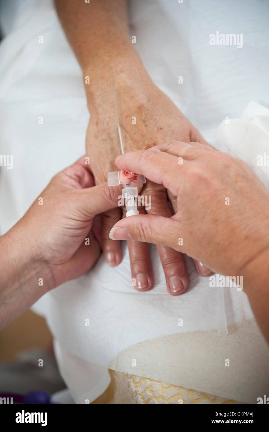 Verpleegkundigen sluiten een infuus aan bij de patient. De ...