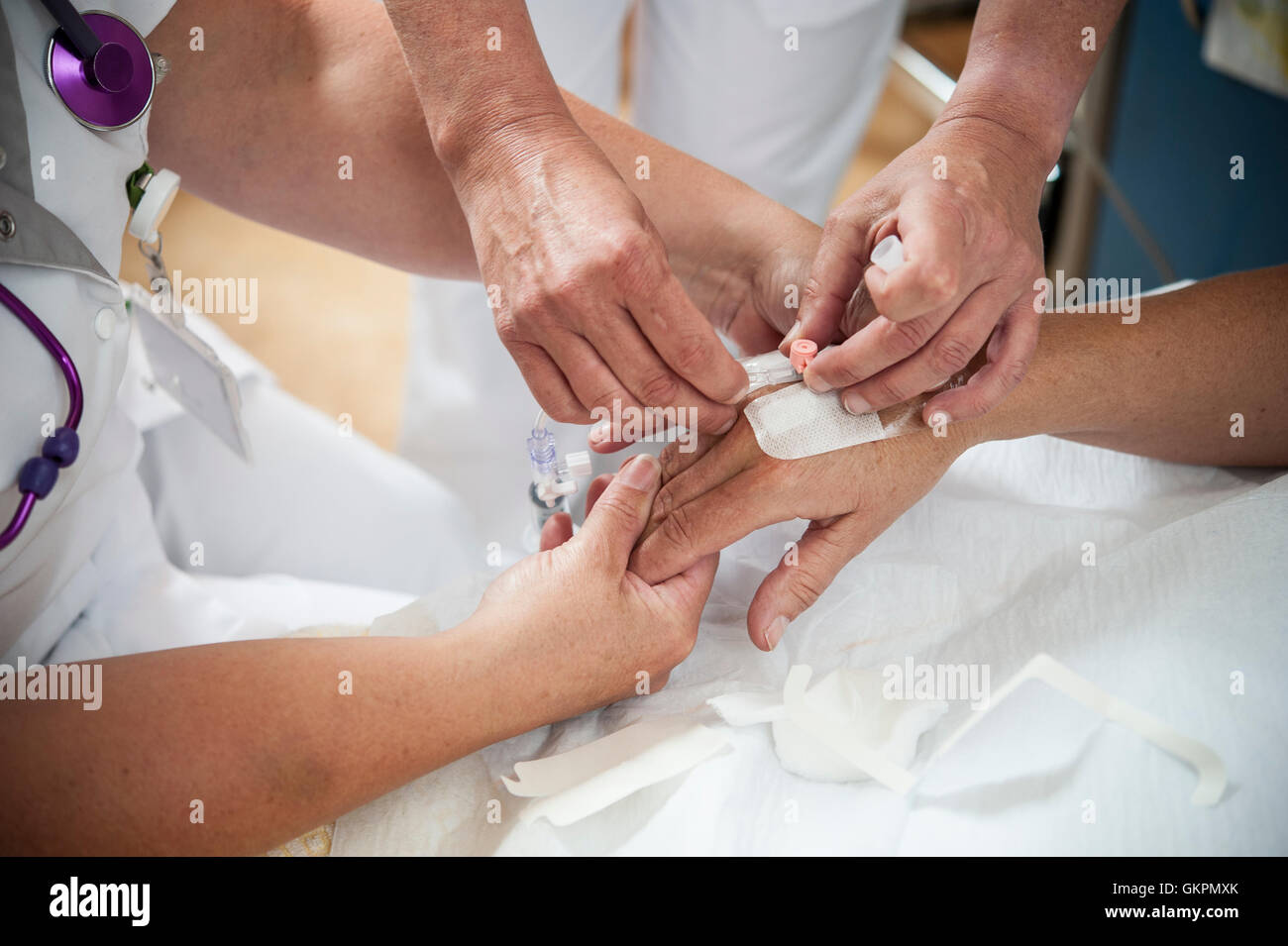 Verpleegkundigen sluiten een infuus aan bij de patient. De ...