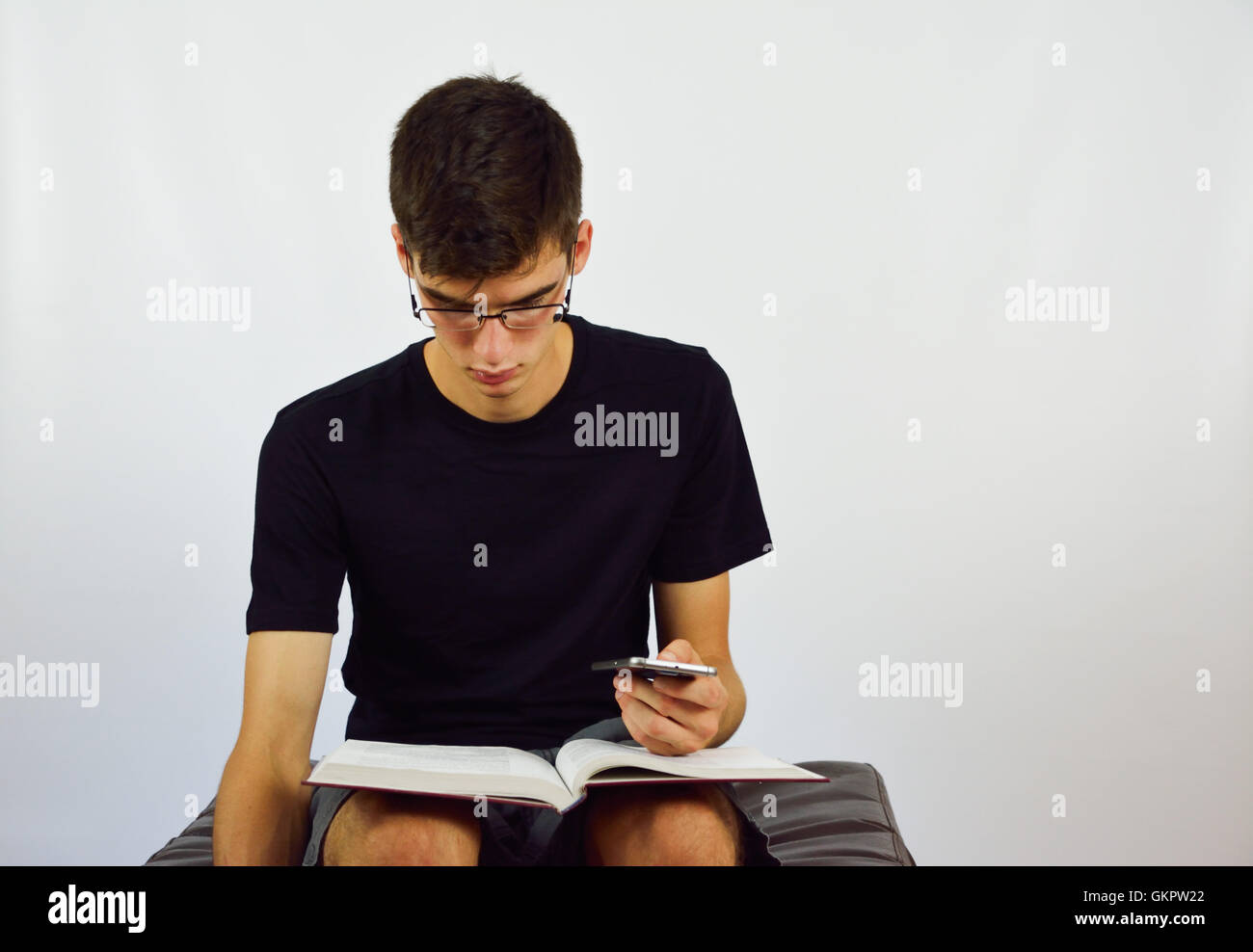 Teenager with book and texting Stock Photo - Alamy