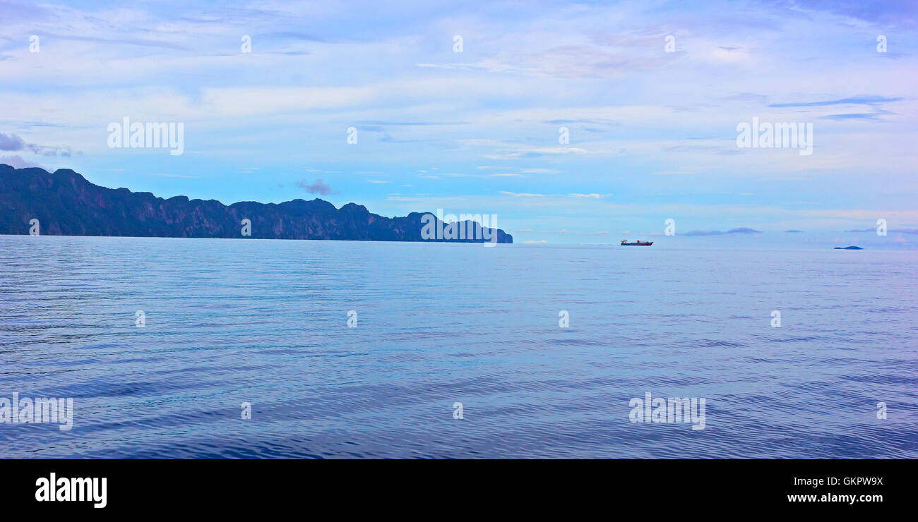 Ship in the sea between the land on horizon Stock Photo - Alamy