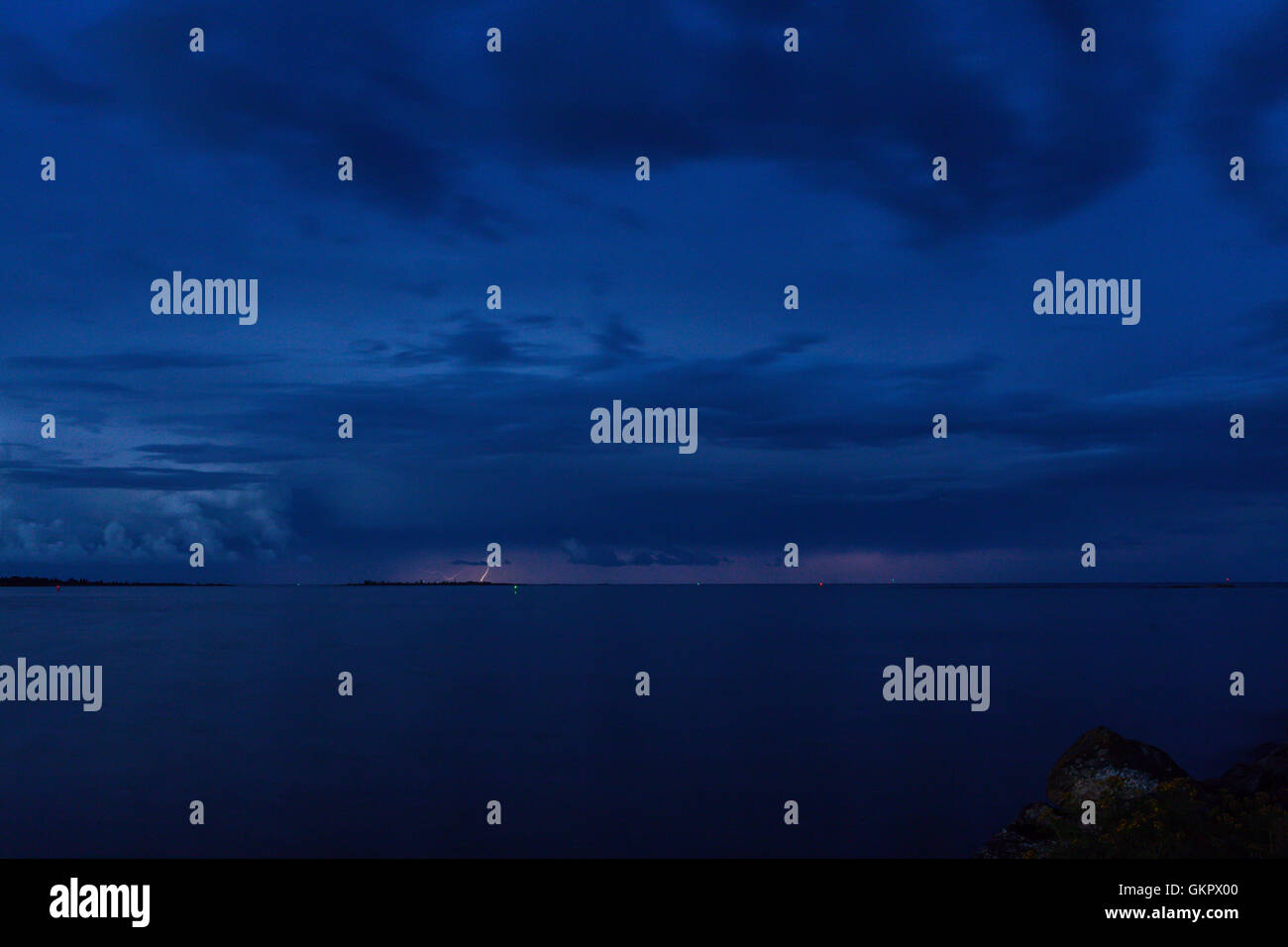 Thunderstorm at sea. Summer night, lights from an inlet and lightning ...