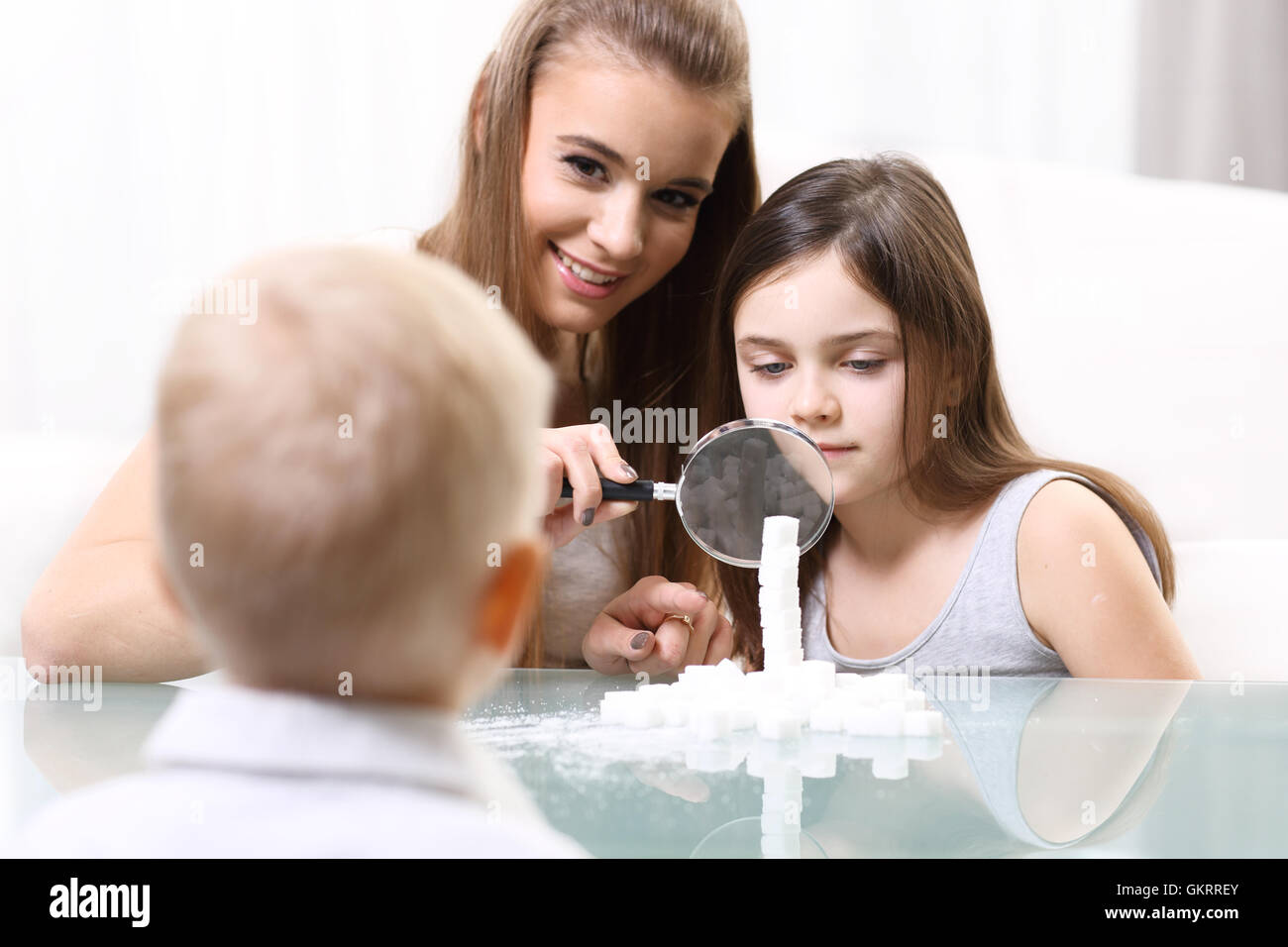 Woman with children looking through a magnifying glass at the table ...