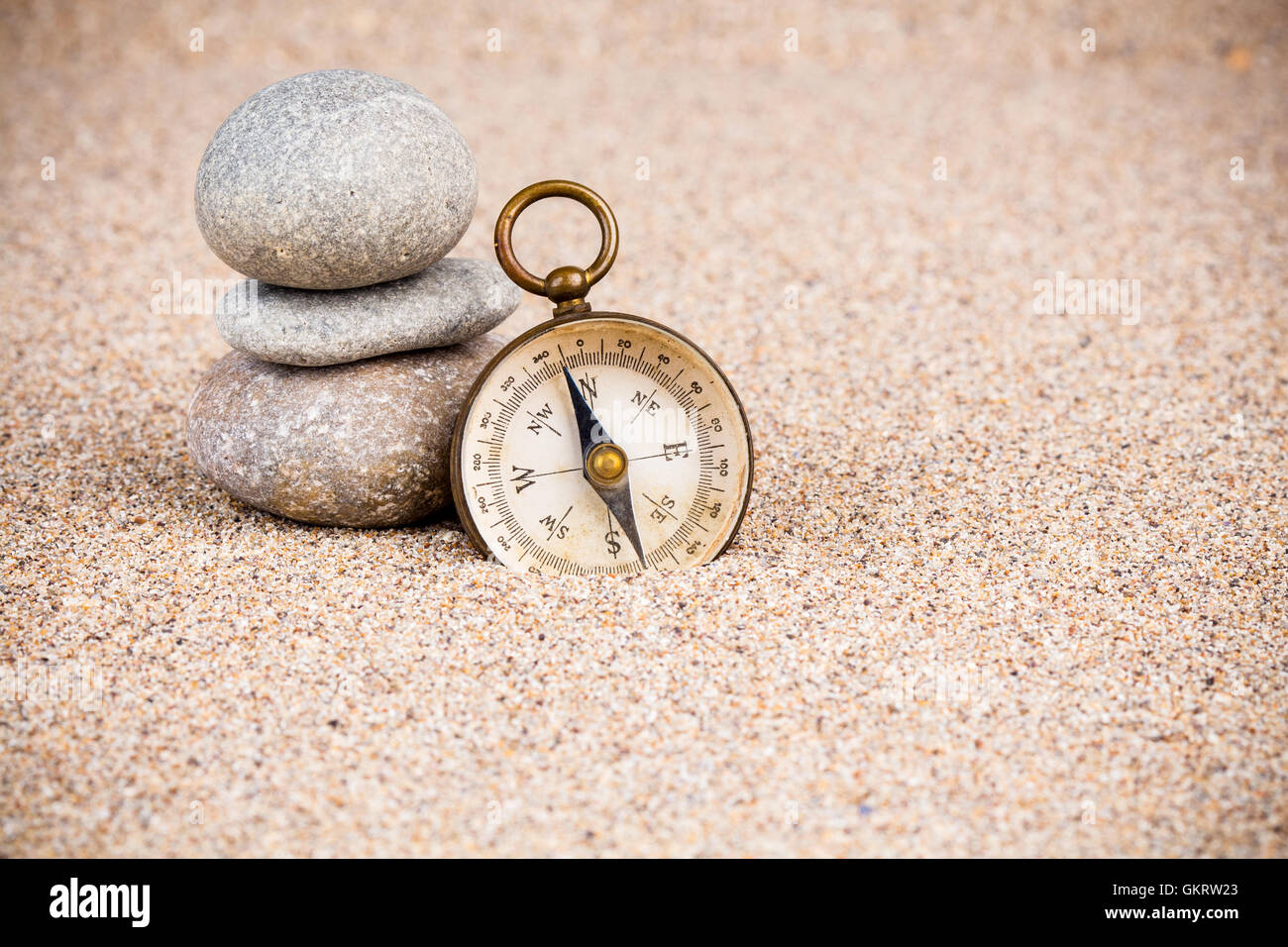 Vintage compass with three pebble stones on sand Stock Photo - Alamy