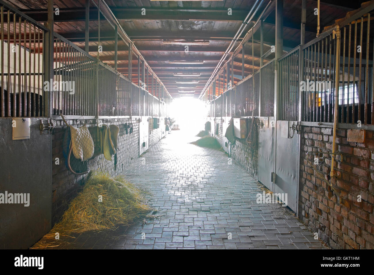 Stable with open gates and bundles of hay on the floor Stock Photo - Alamy