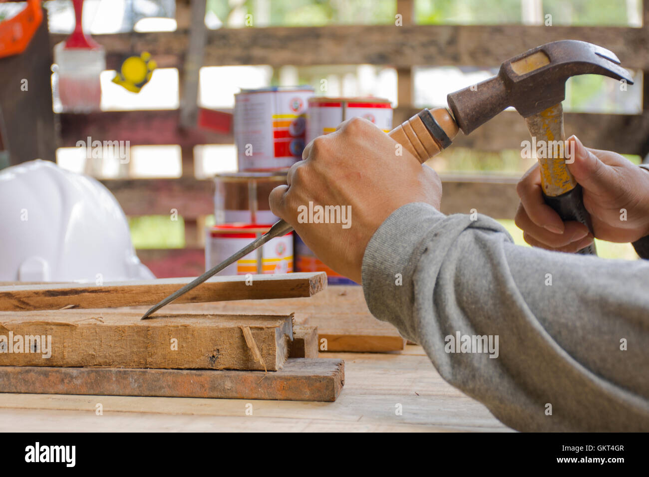 Carpenter using chisel and hammer in his hand with plank.Close up and ...
