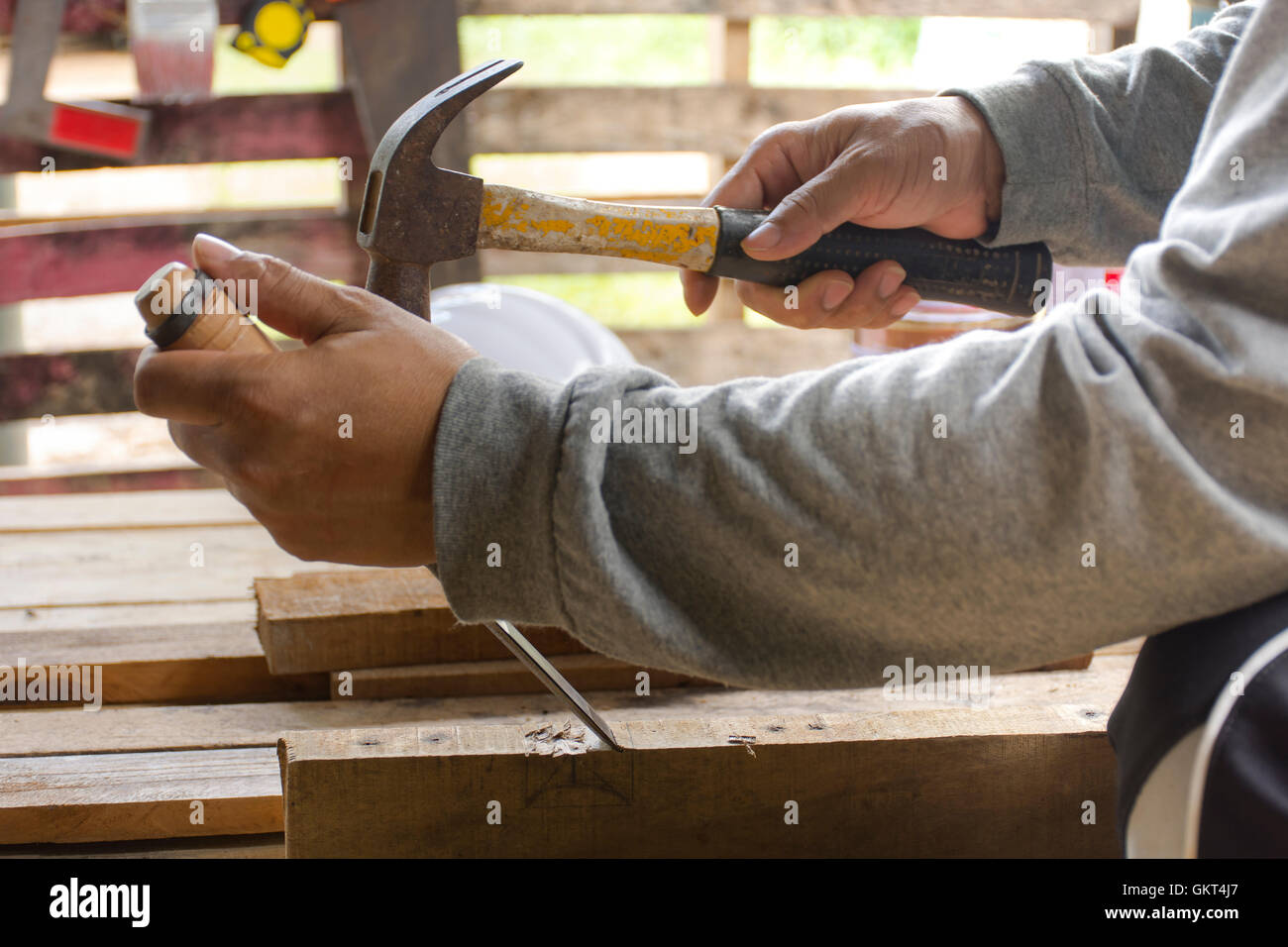 Carpenter using chisel and hammer in his hand with plank.Close up and ...