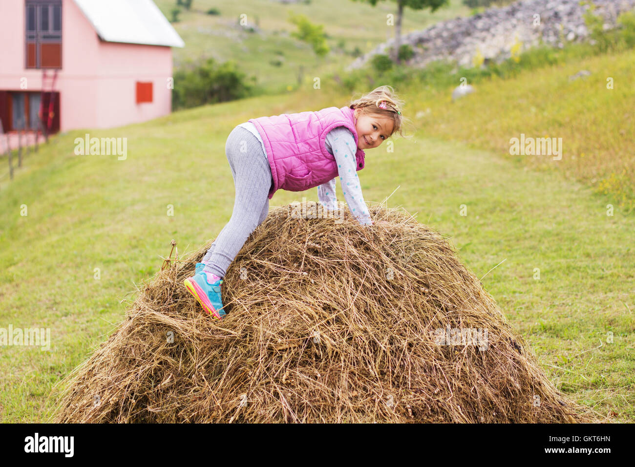 Little Girl playing on a haystack in a meadow, child outdoor activity ...