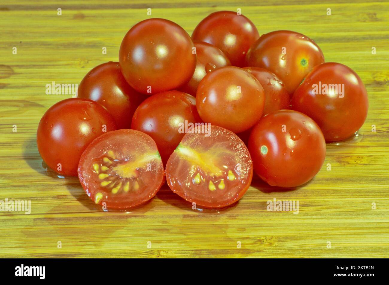 Cherry tomatoes on a wood cutting board under artificial light Stock ...