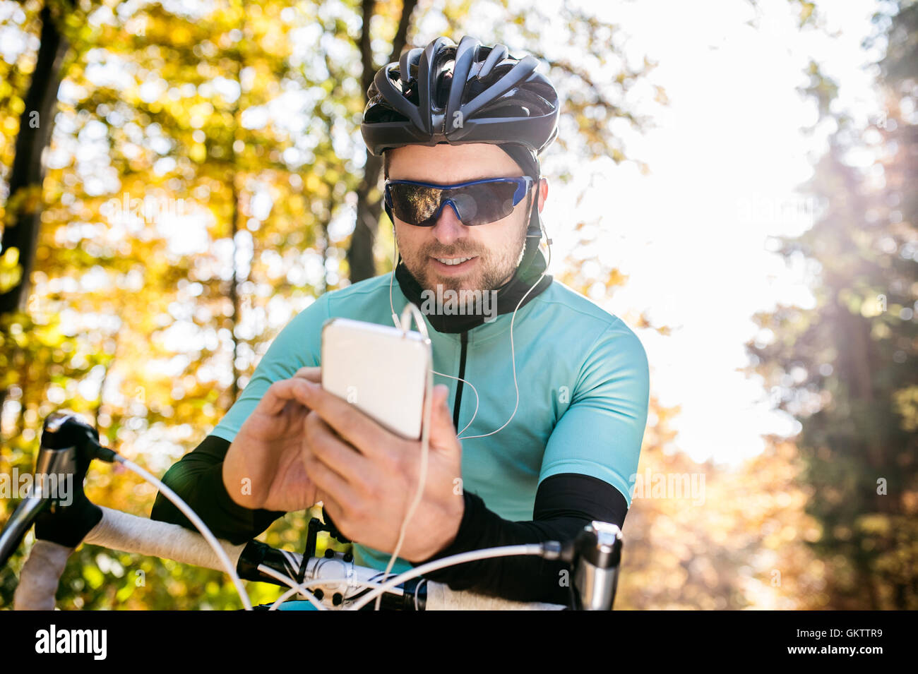 Young sportsman riding bicycle, holding smartphone, sunny autumn Stock ...