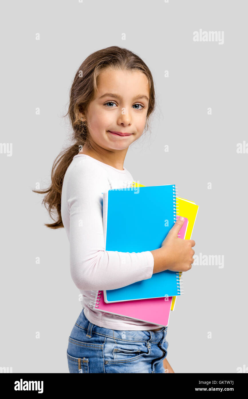 Smiling little student girl holding notebooks Stock Photo - Alamy