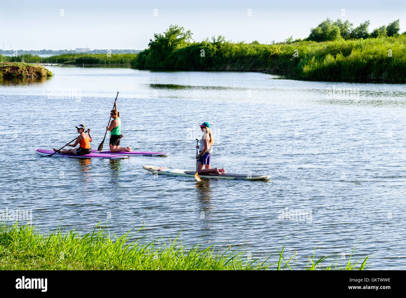 Three young Caucasian women enjoy paddle boarding on the North Canadian ...