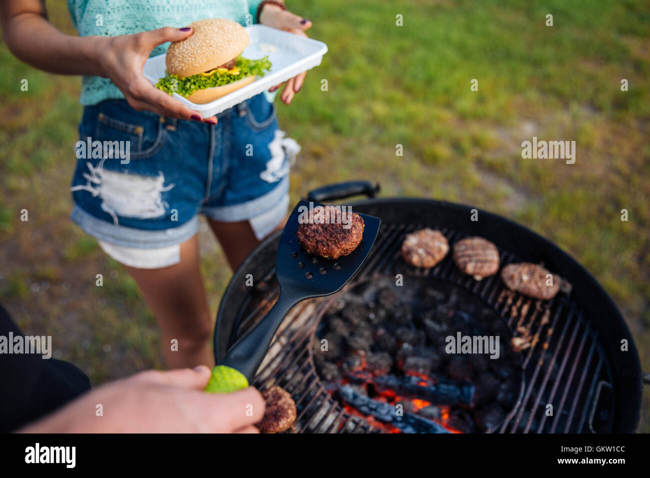 Top view of young people cooking meet on barbeque grill and making ...
