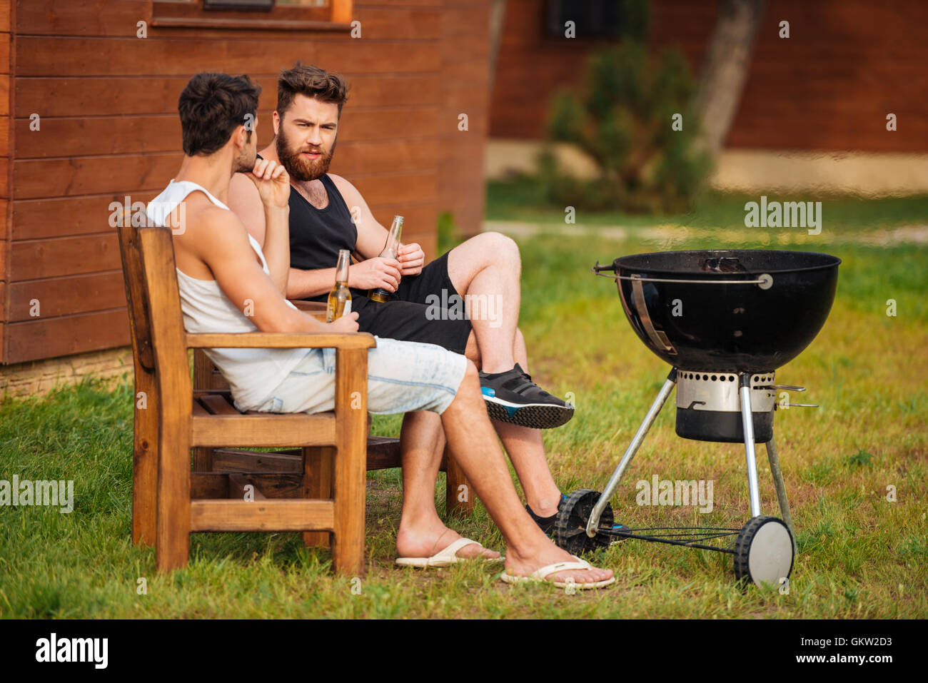 Two young men talking while preparing barbecue grill in park zone Stock ...