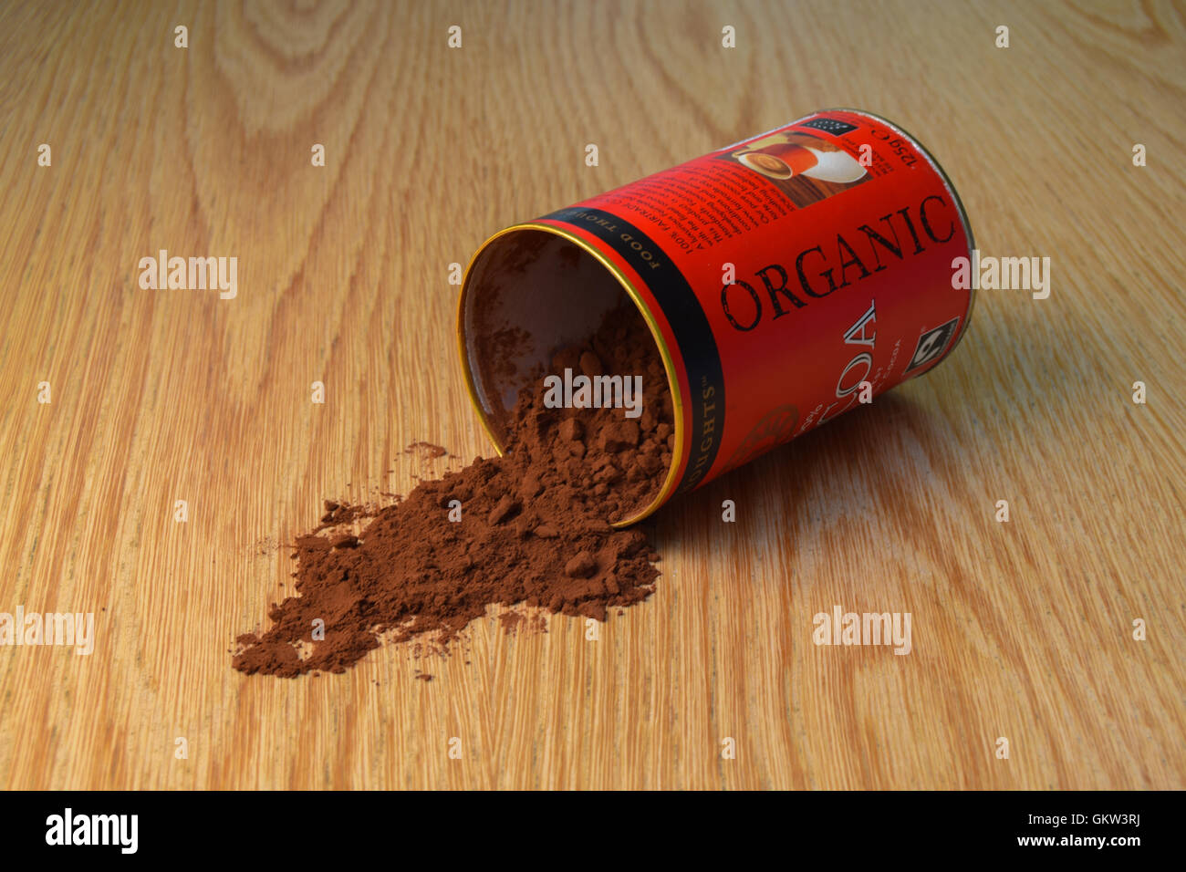 Tin of organic coco powder knocked over on wooden table, powder spill ...