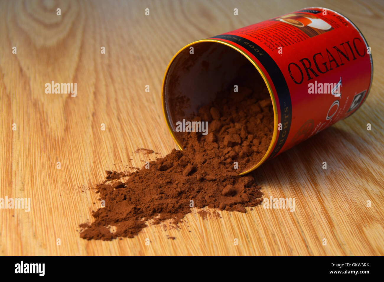 Tin of organic coco powder knocked over on wooden table, powder spill ...