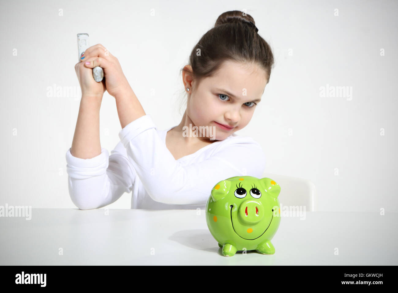 Little girl breaking piggy bank isolated on white Stock Photo - Alamy
