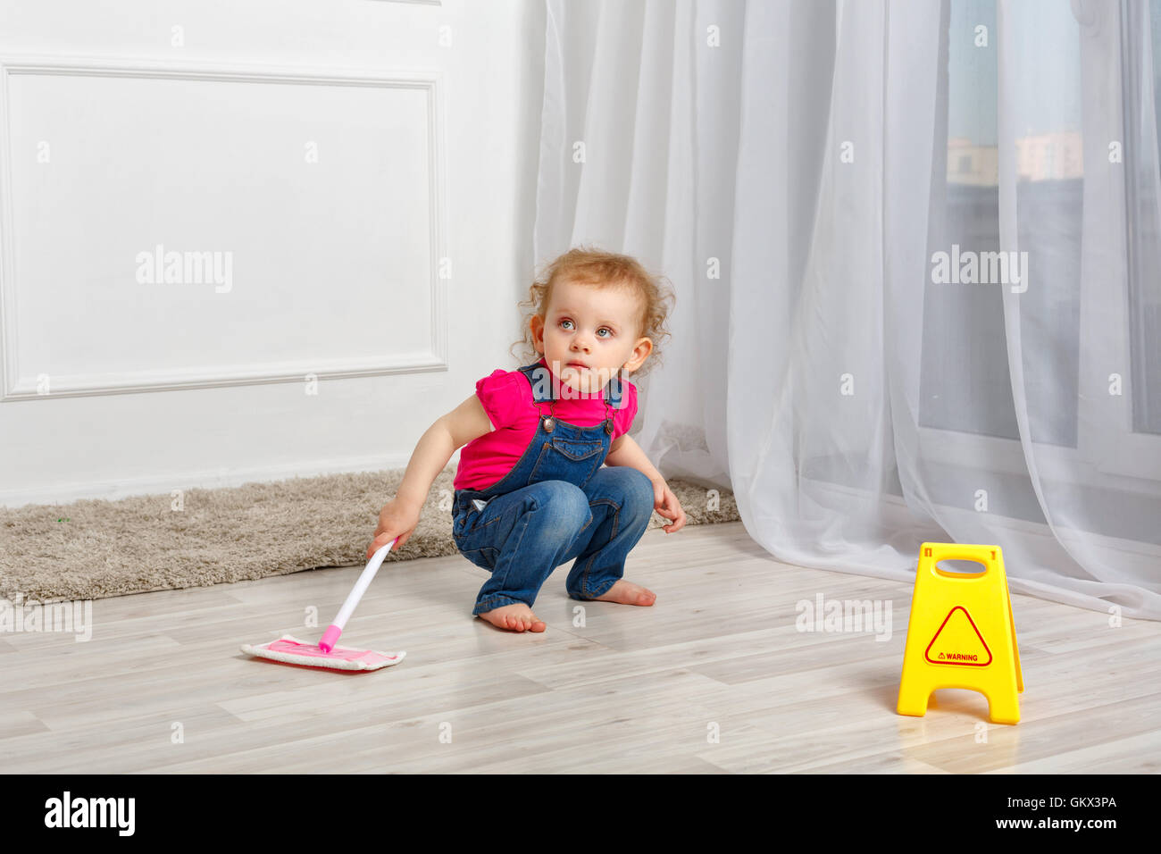 Little girl is cleaned with a mop in her hands. Little helper ...