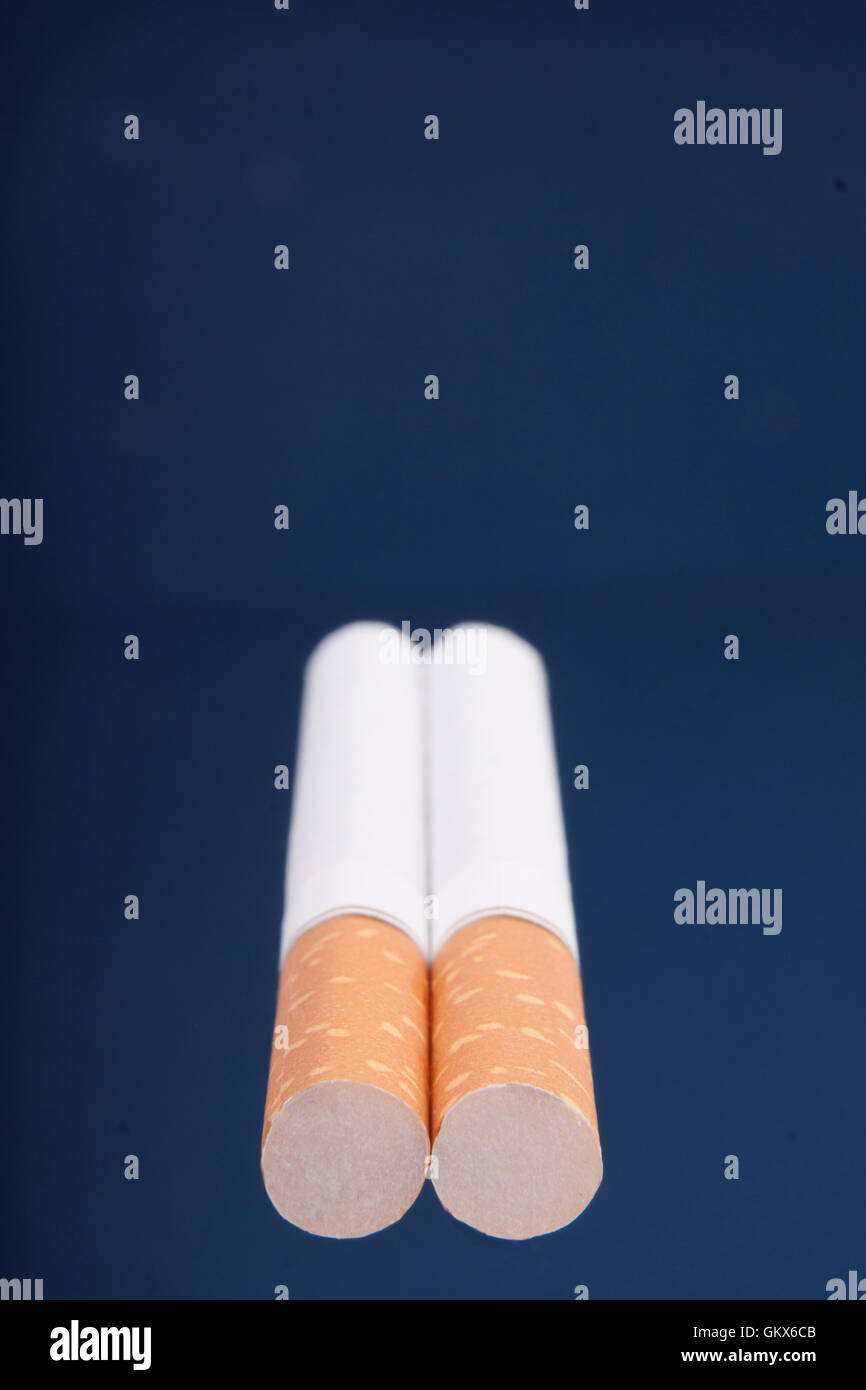Two cigarettes on blue background Stock Photo - Alamy