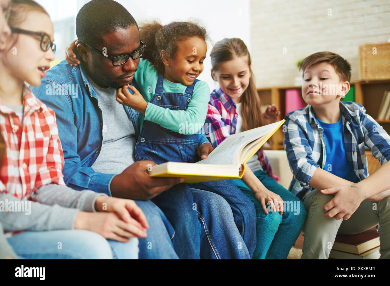 Little pupils and their teacher reading book Stock Photo - Alamy