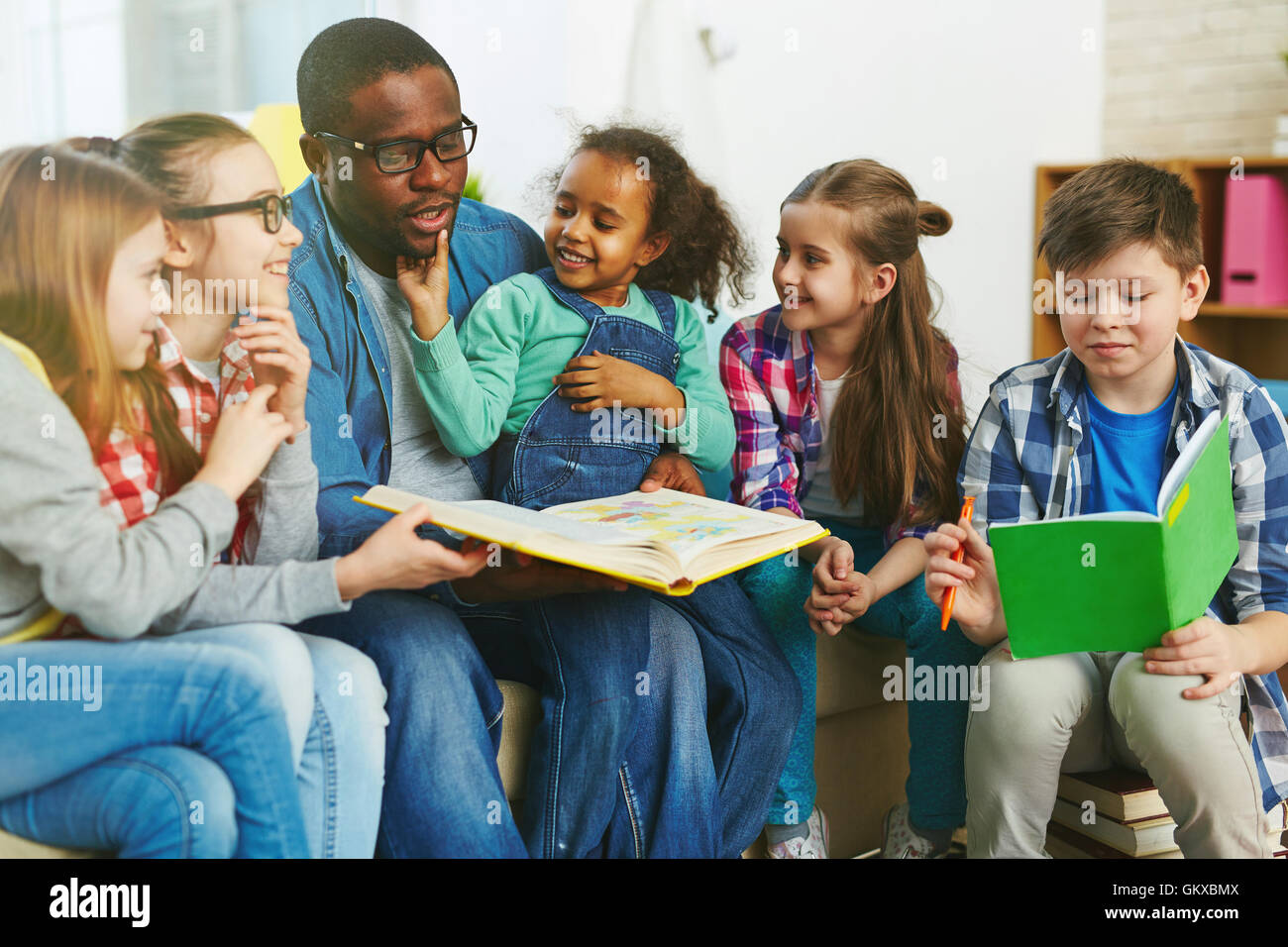 Group of cute schoolkids reading with teacher Stock Photo - Alamy
