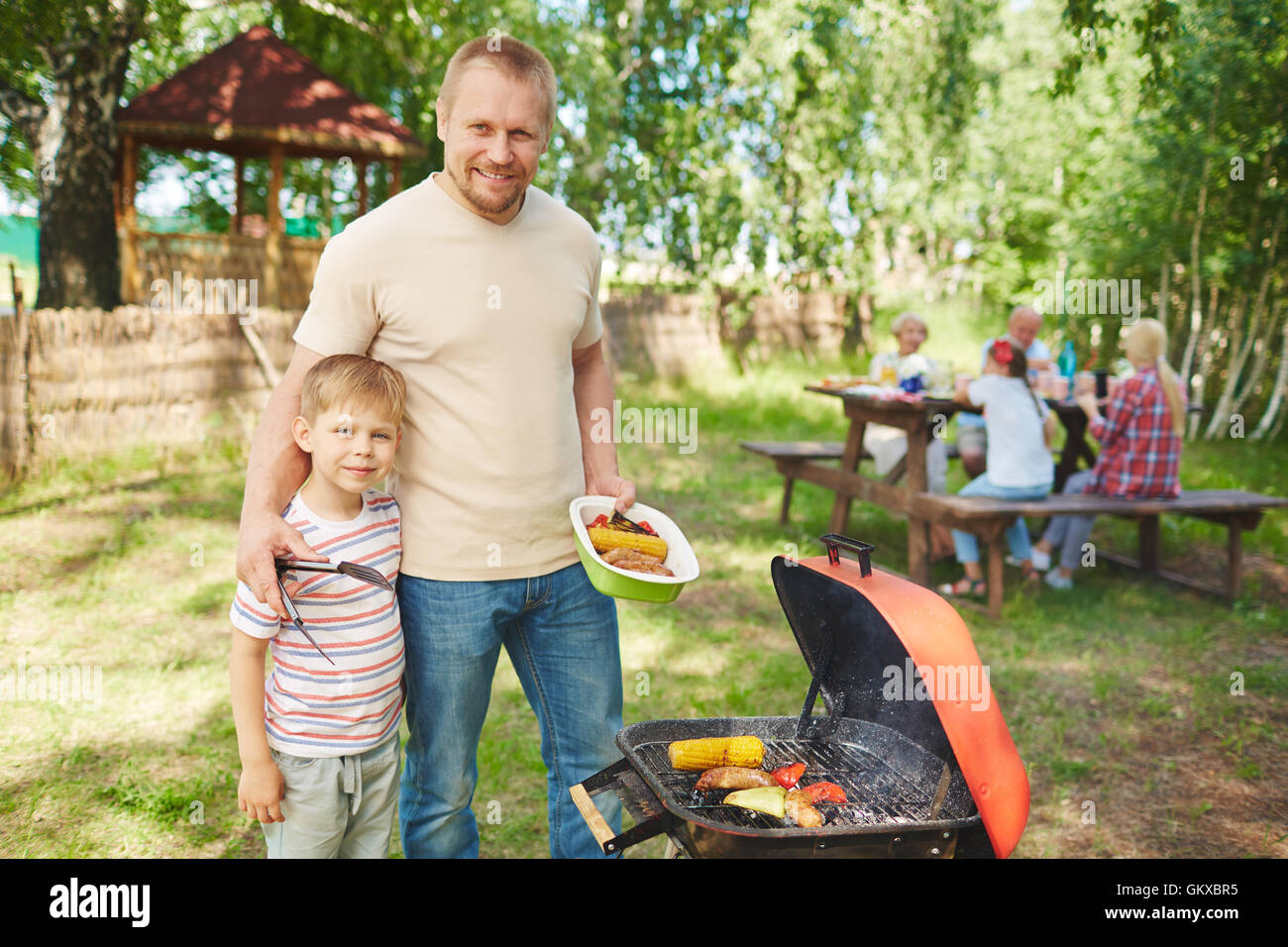 Father cooking meat outdoors with his son Stock Photo - Alamy