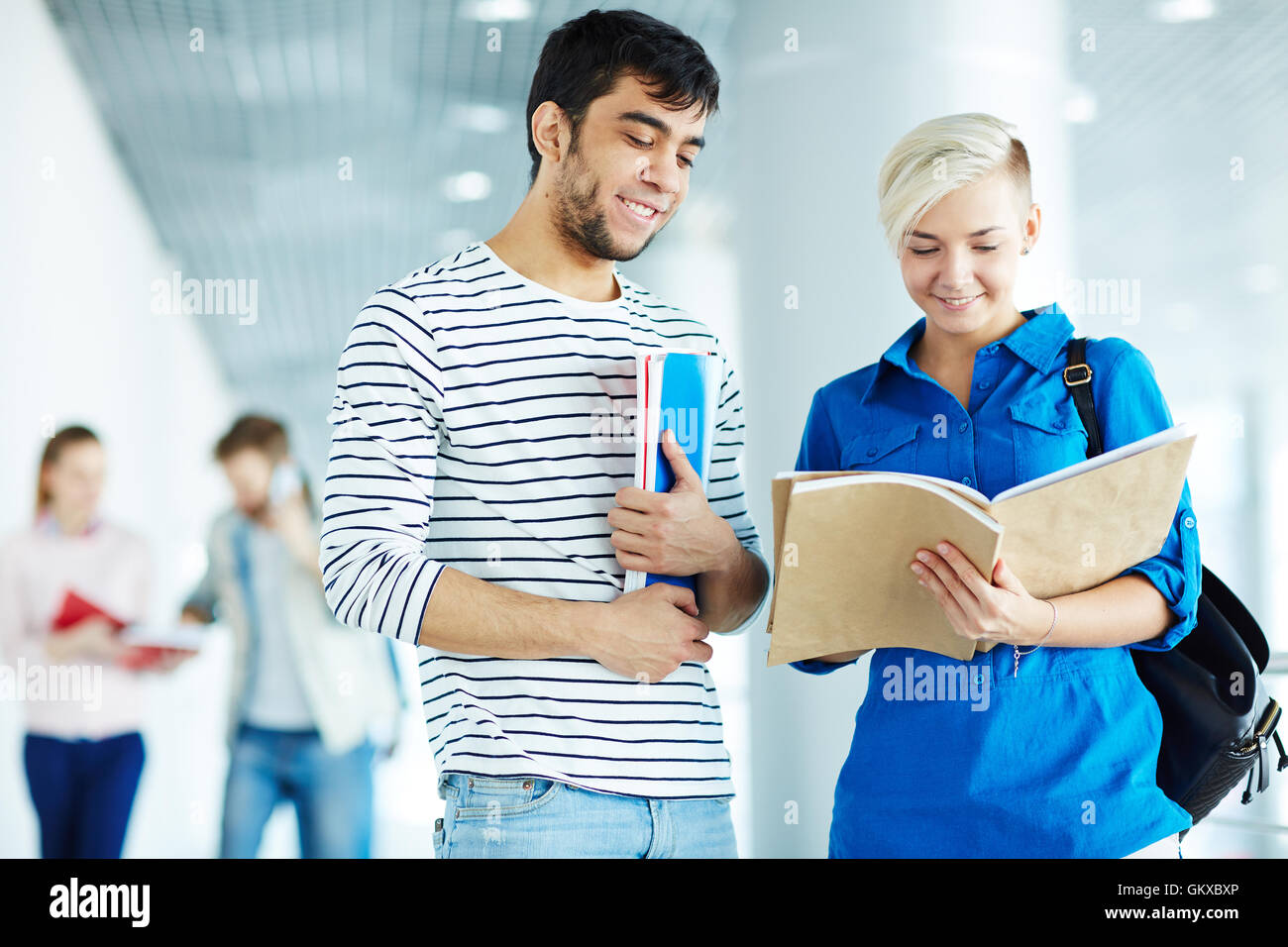 Friends discussing text in book during break Stock Photo - Alamy