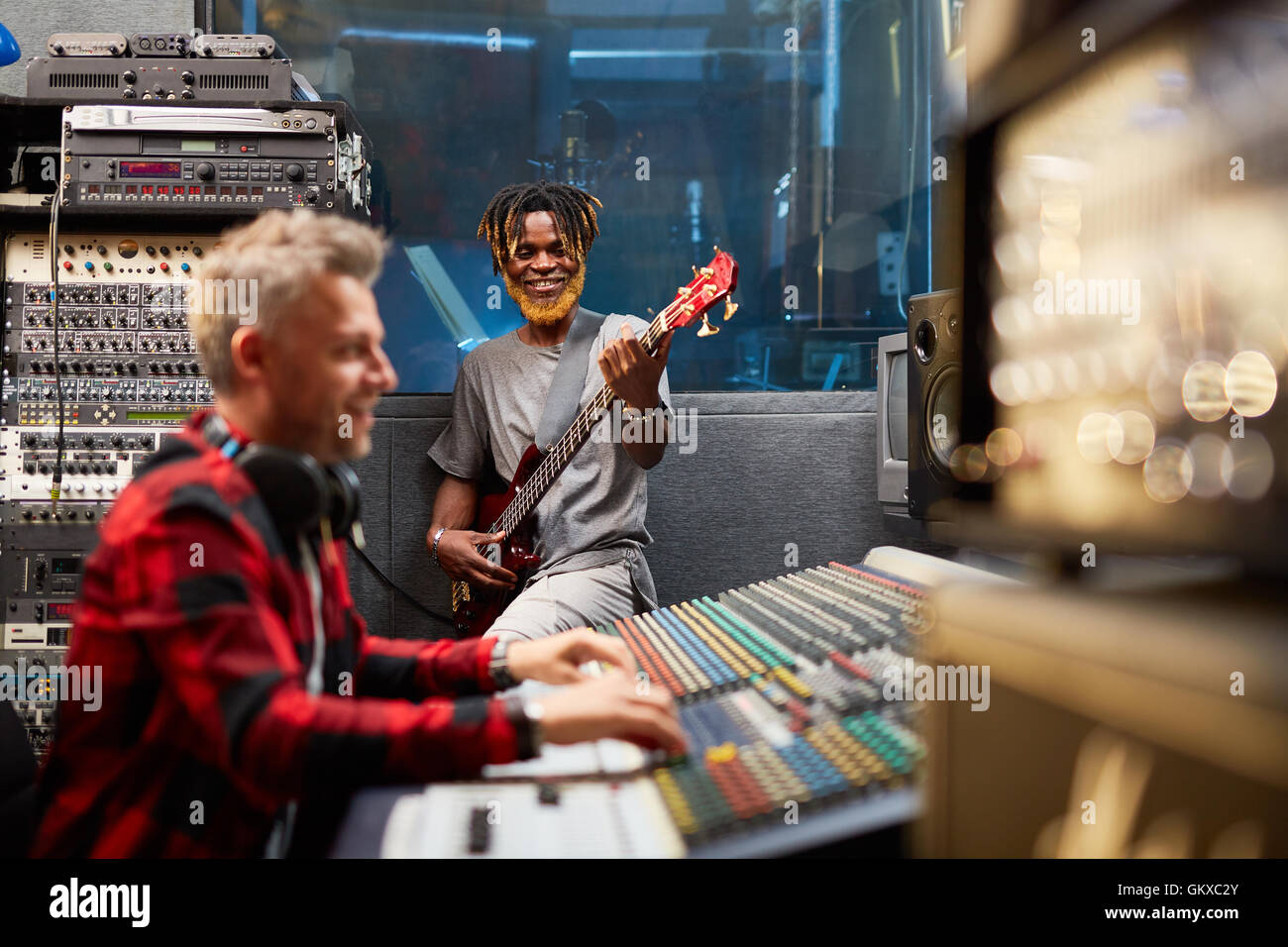 African musician playing guitar while producer recording him in studio ...