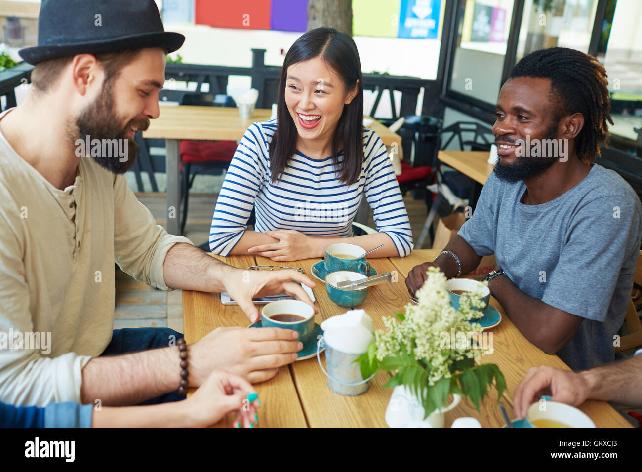 Three friends laughing during conversation in cafe Stock Photo - Alamy